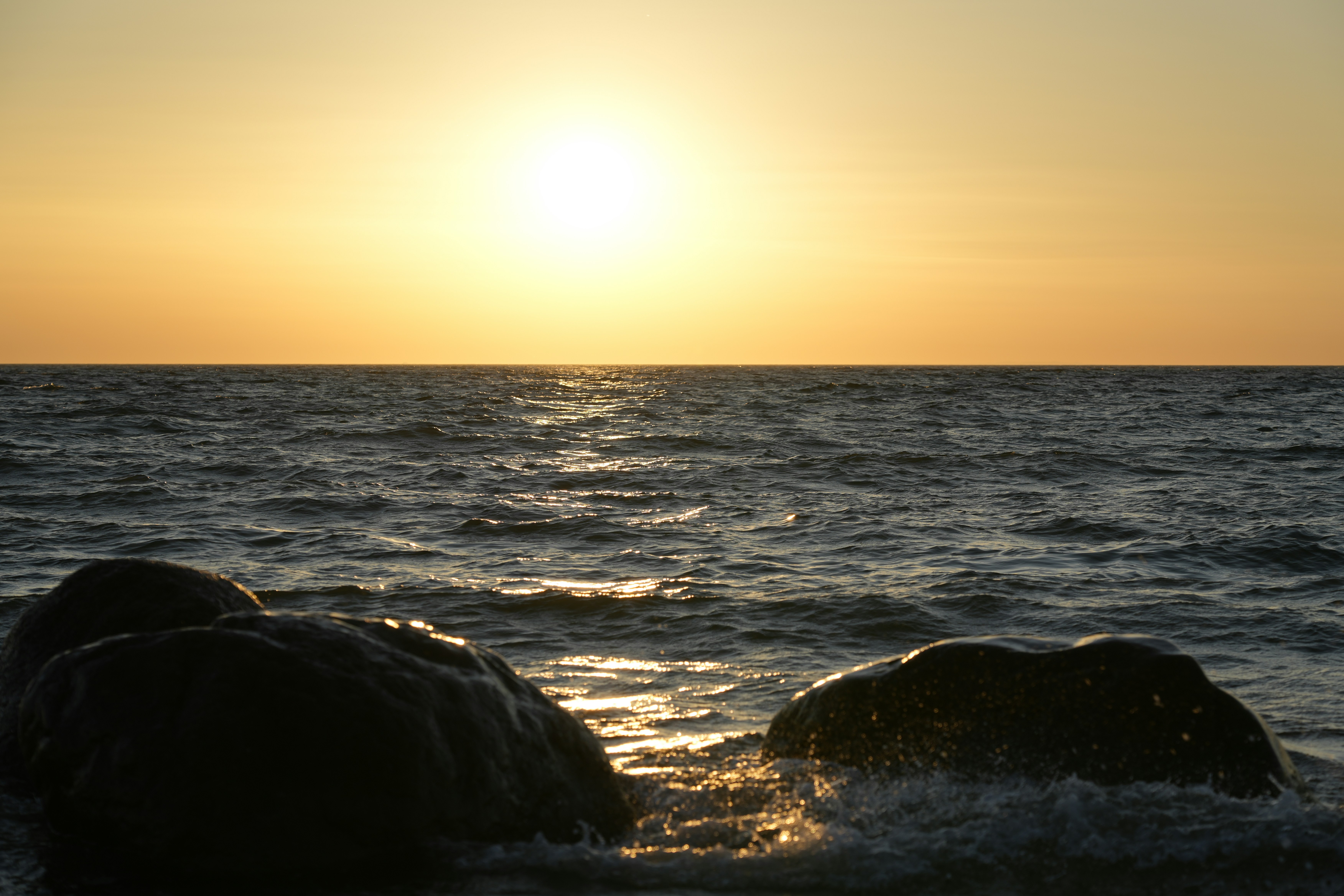 Sunlit Crest: Rocks, Sea, and a Quiet Horizon