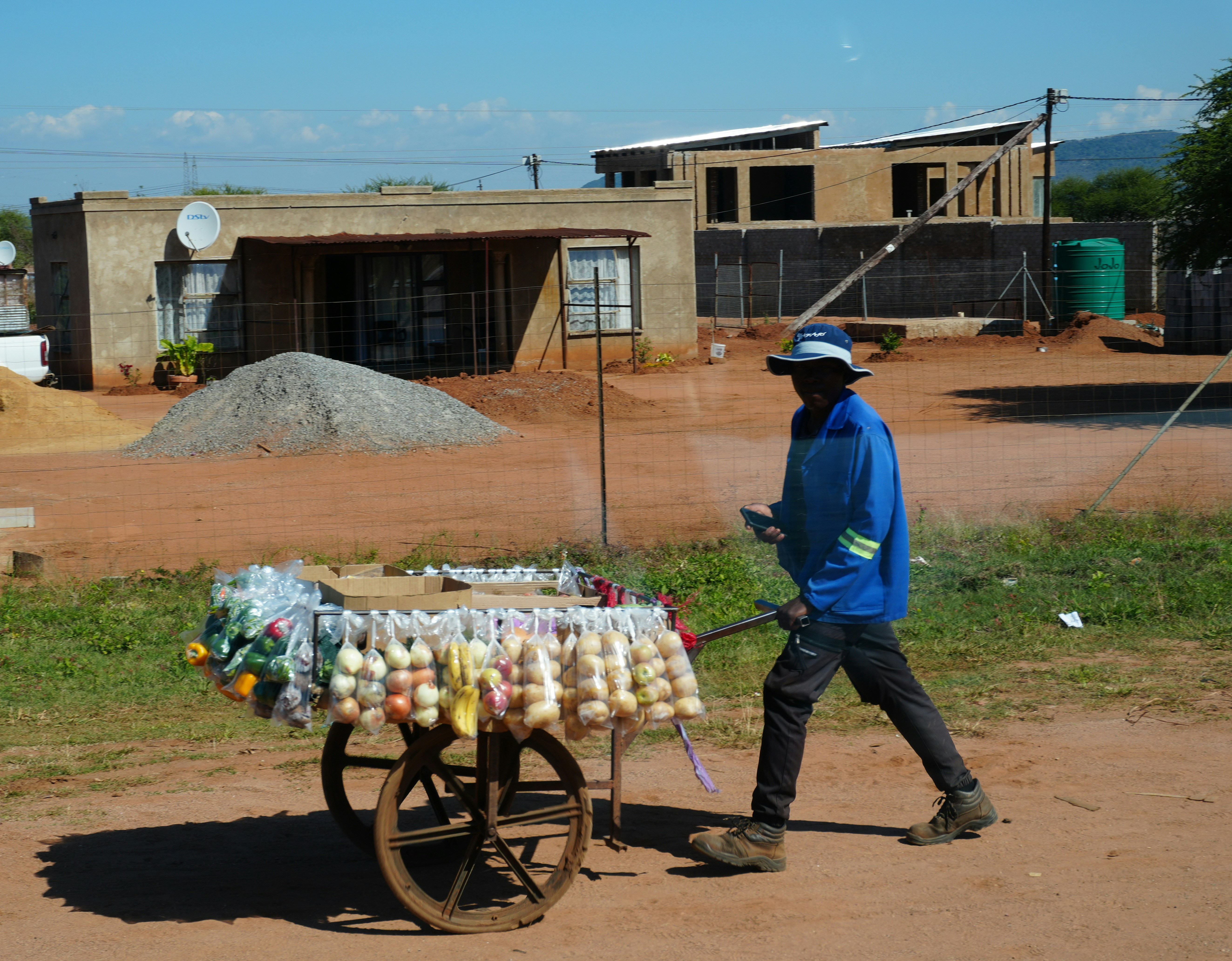 Street Vendor in a Sunlit Outback: Cart with Hanging Produce