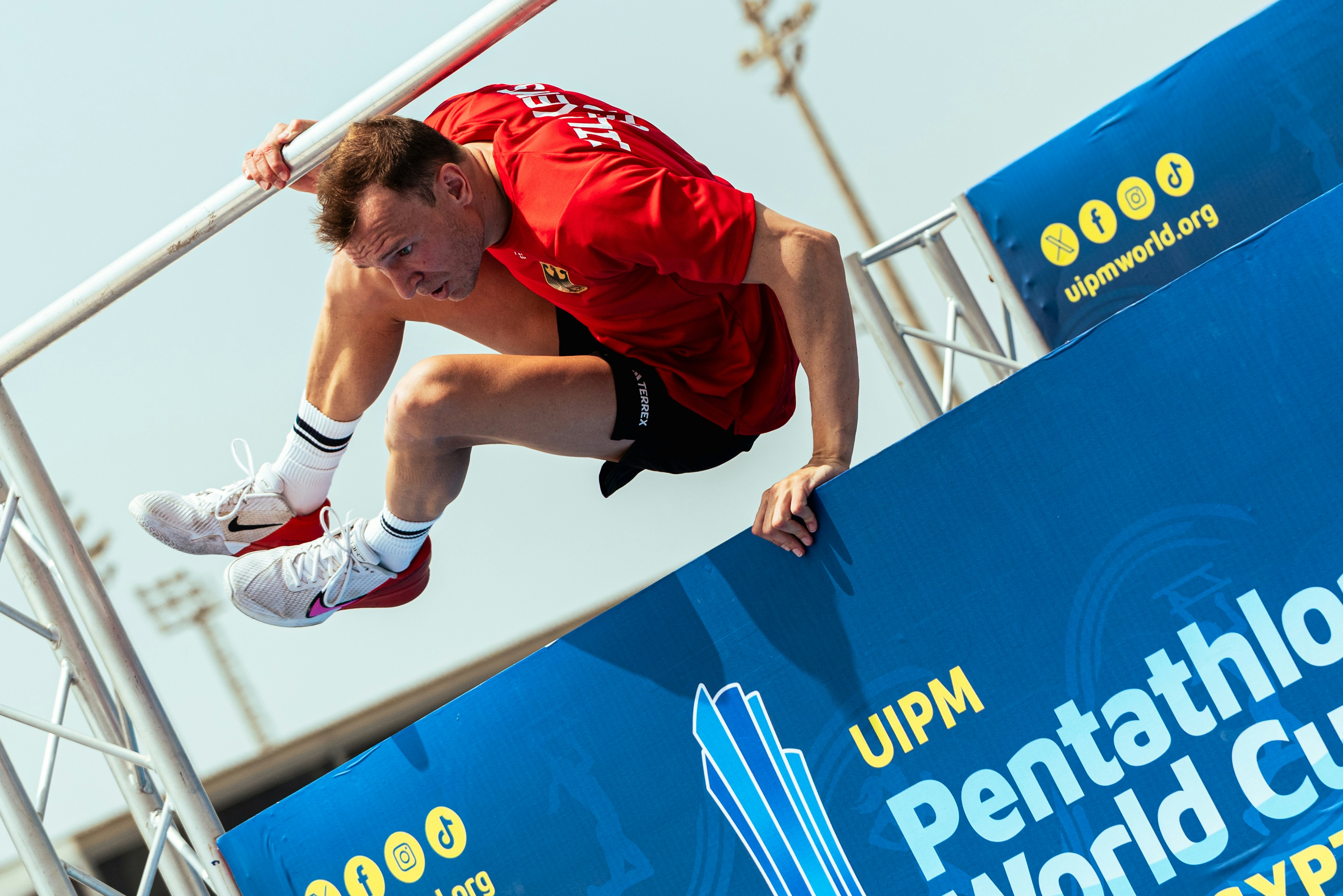 Leap of Speed: A Red-Roled Athlete Hurdles the Barrier