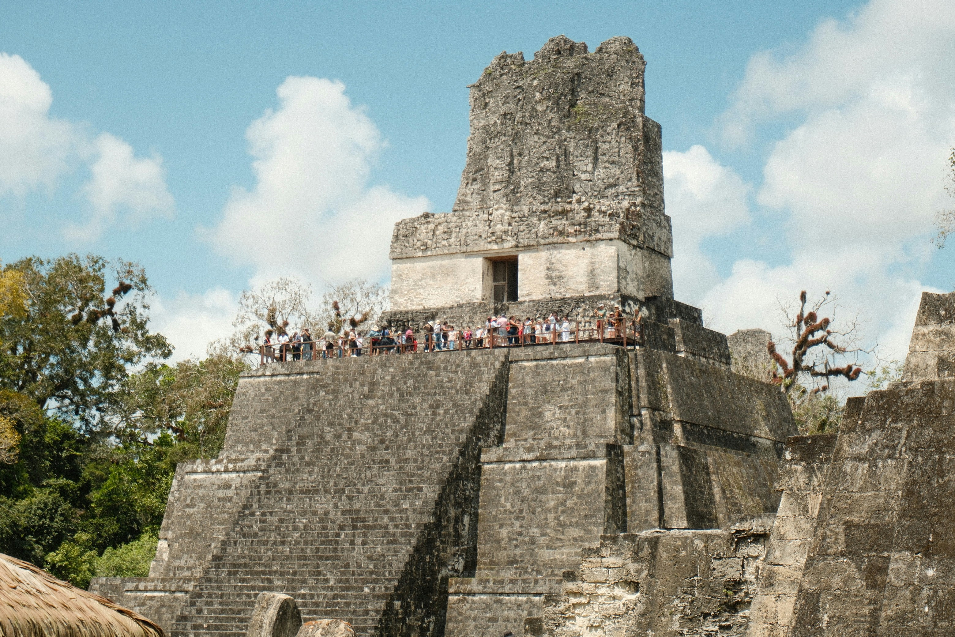 Ancient mayan temple with tourists under a blue sky.