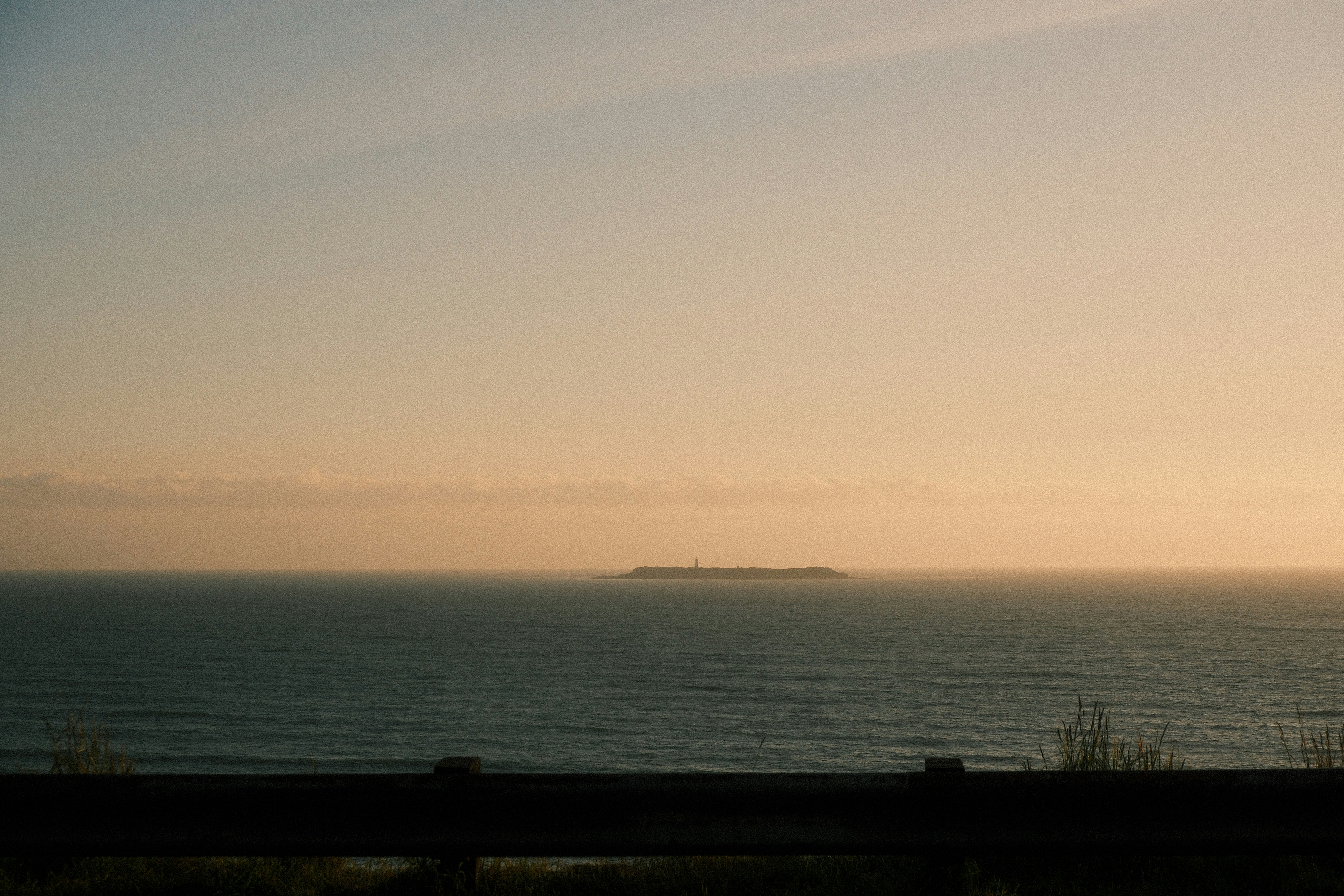Island Horizon: Quiet Sea Between Dusk and Distant Light