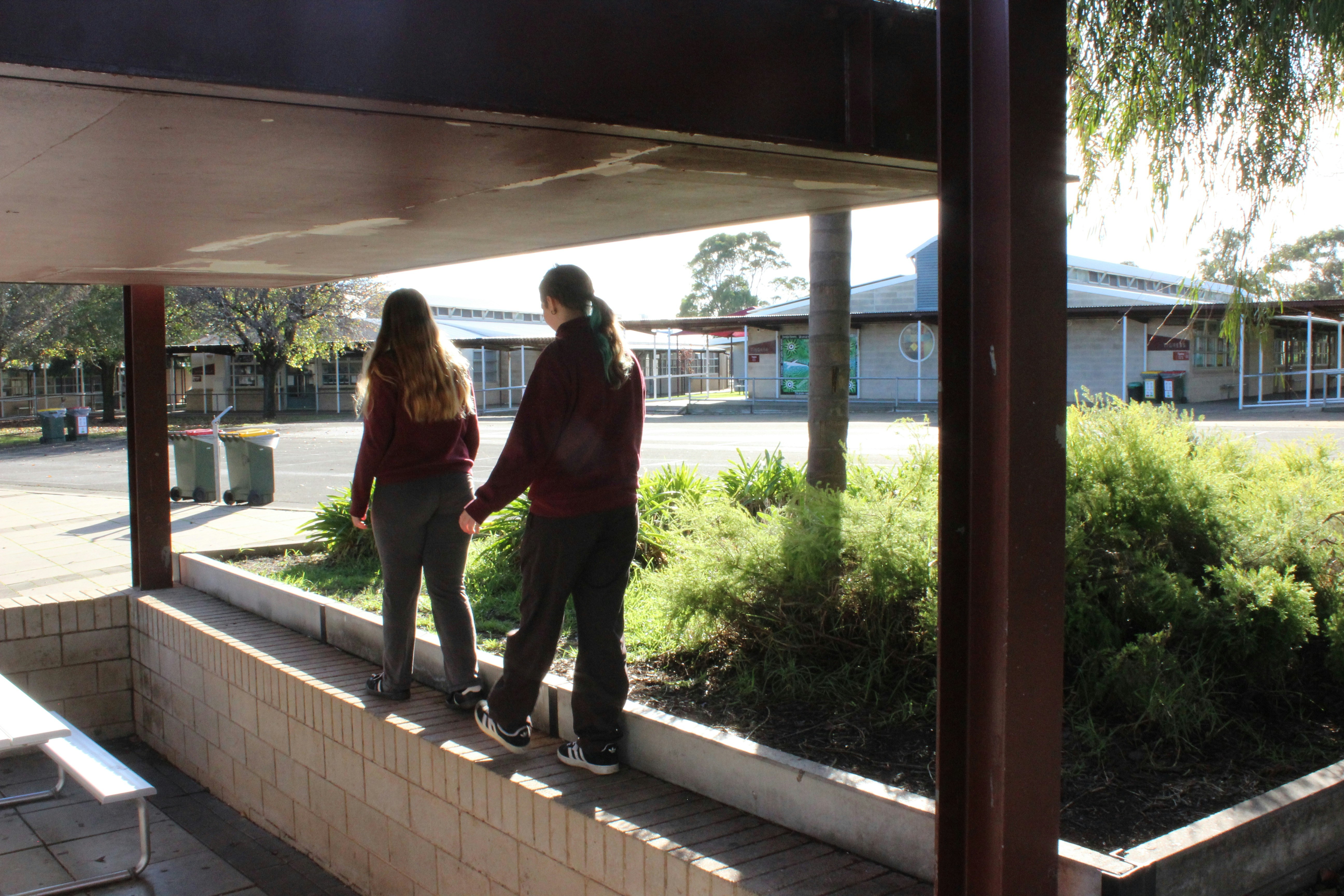 Shared Silence: Two Students Stand in the School Courtyard