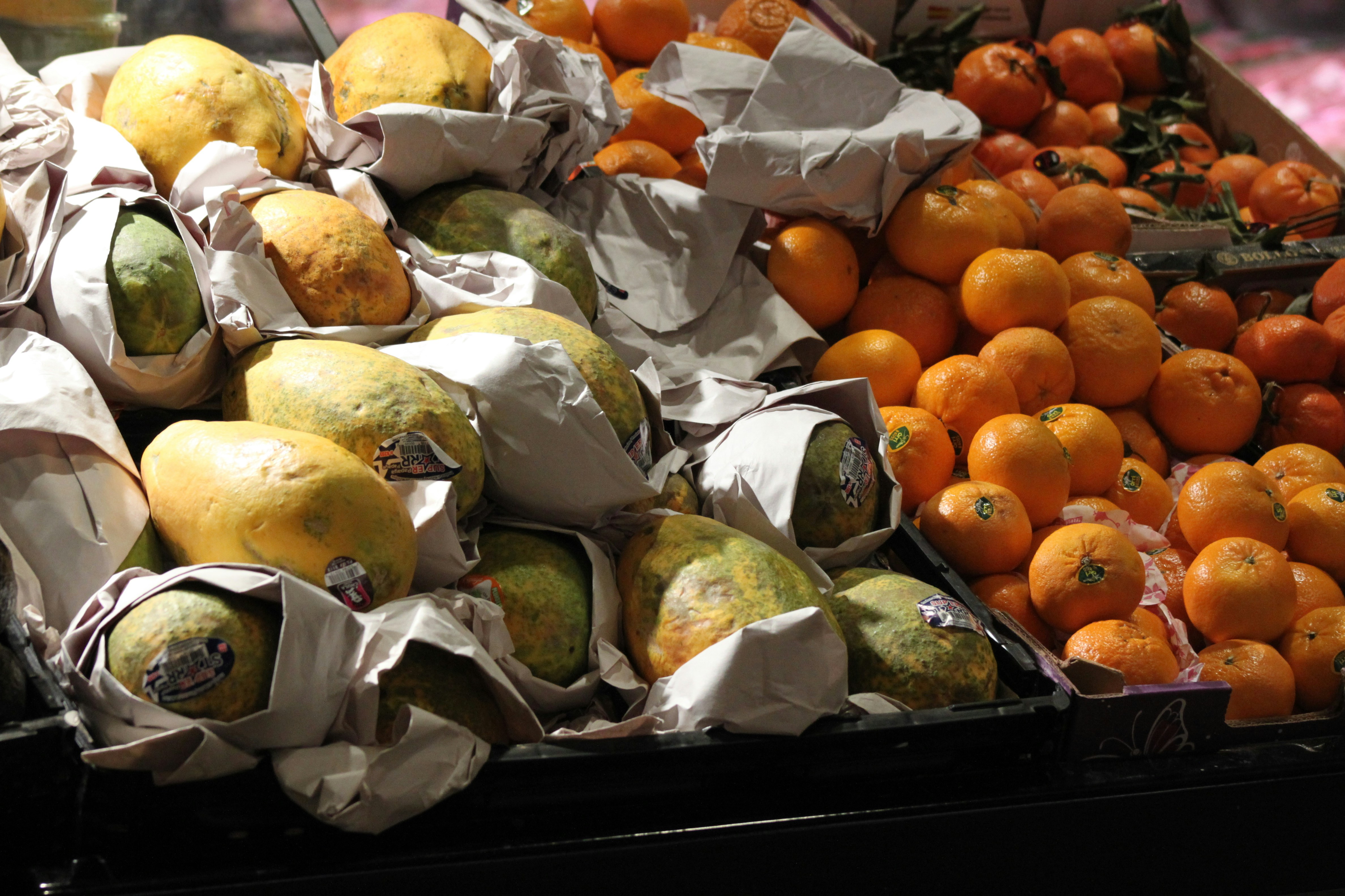 Citrus and wrapped mangoes in a market display