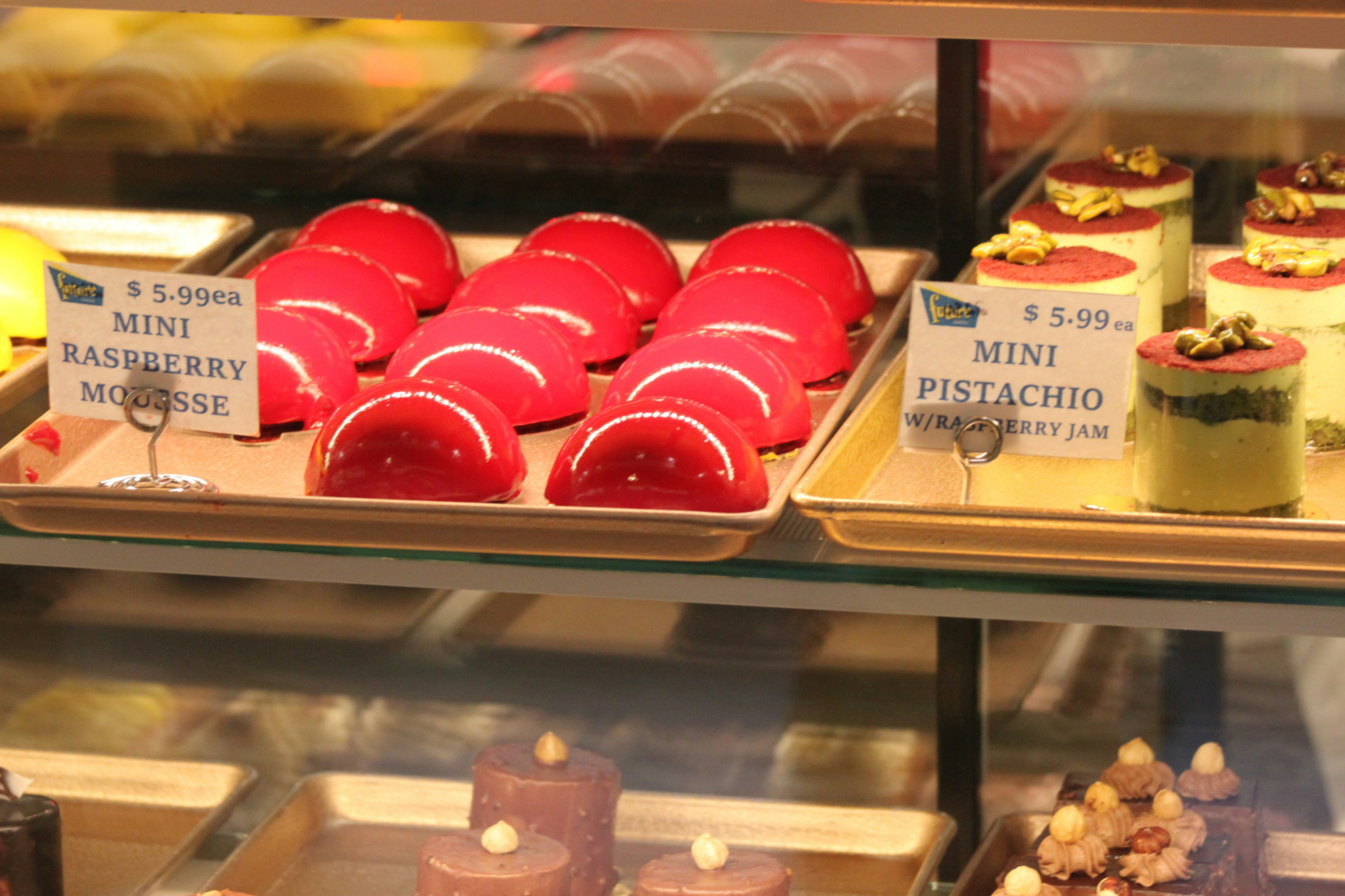 Glossy Raspberry Mousse Glimmers Under Bakery Lights
