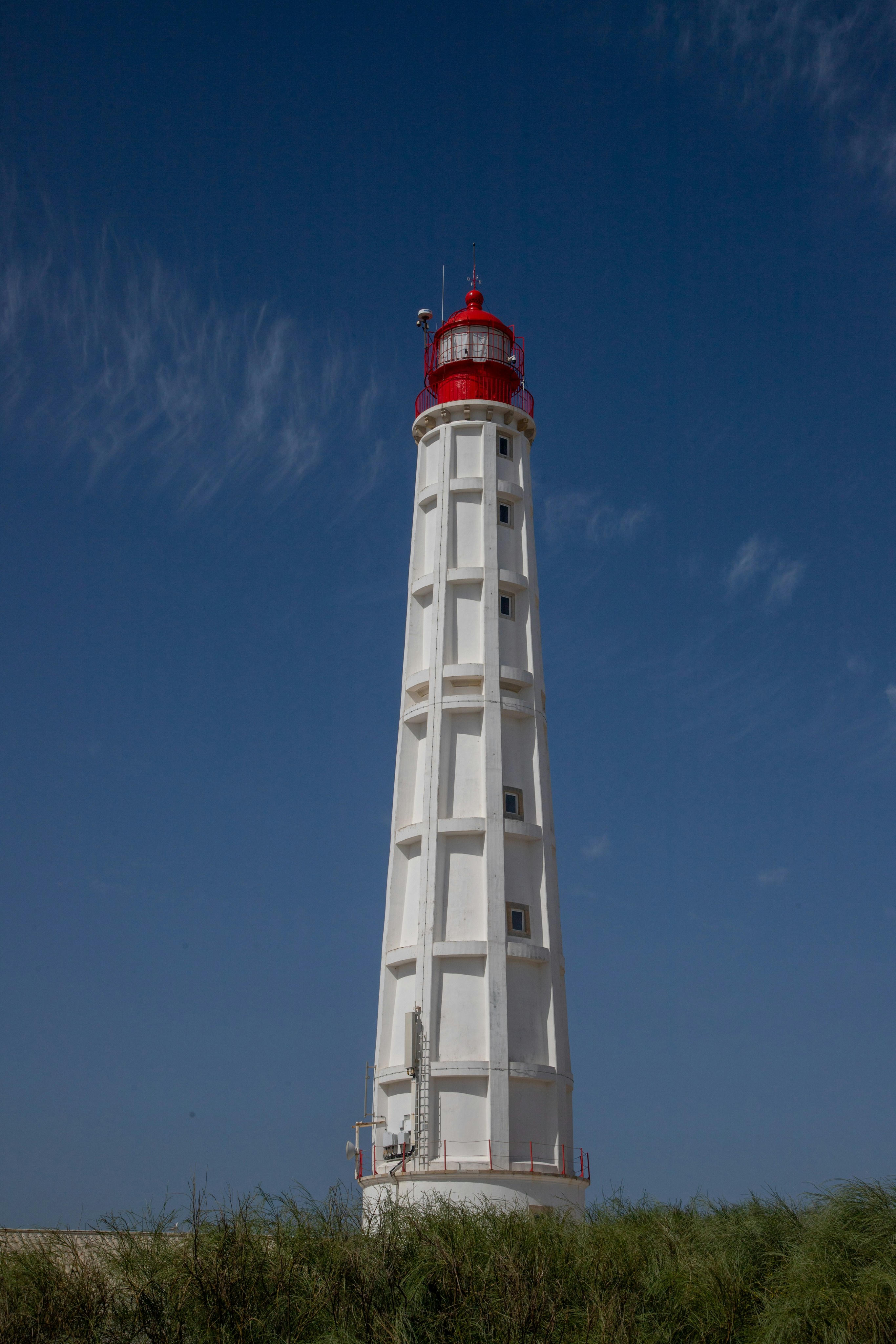 Red Beacon Against Blue Sky: A Coastline Lighthouse Stands Tall