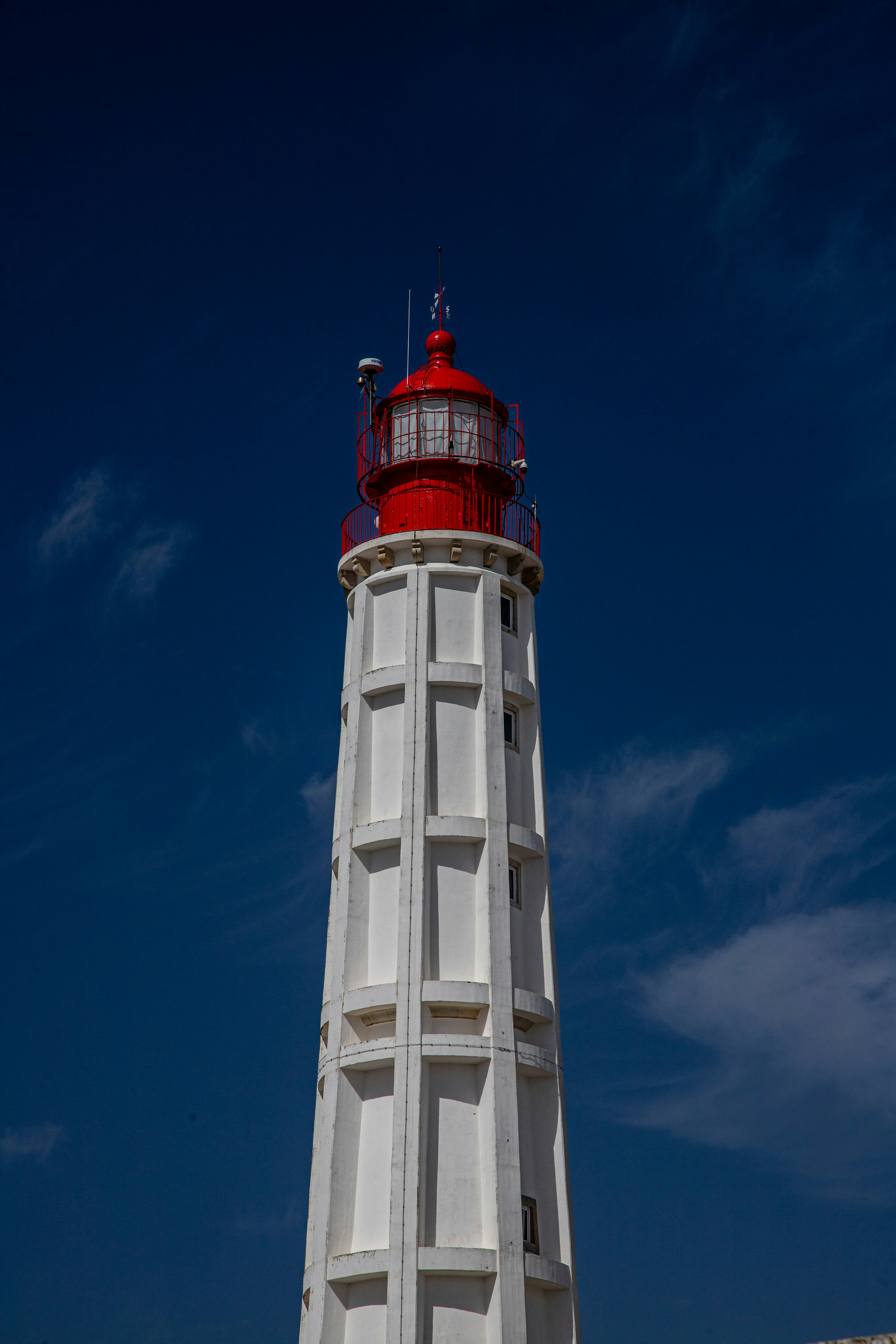 Red Beacon on Blue Canvas: A Coastal Lighthouse Reaches Toward the Sky