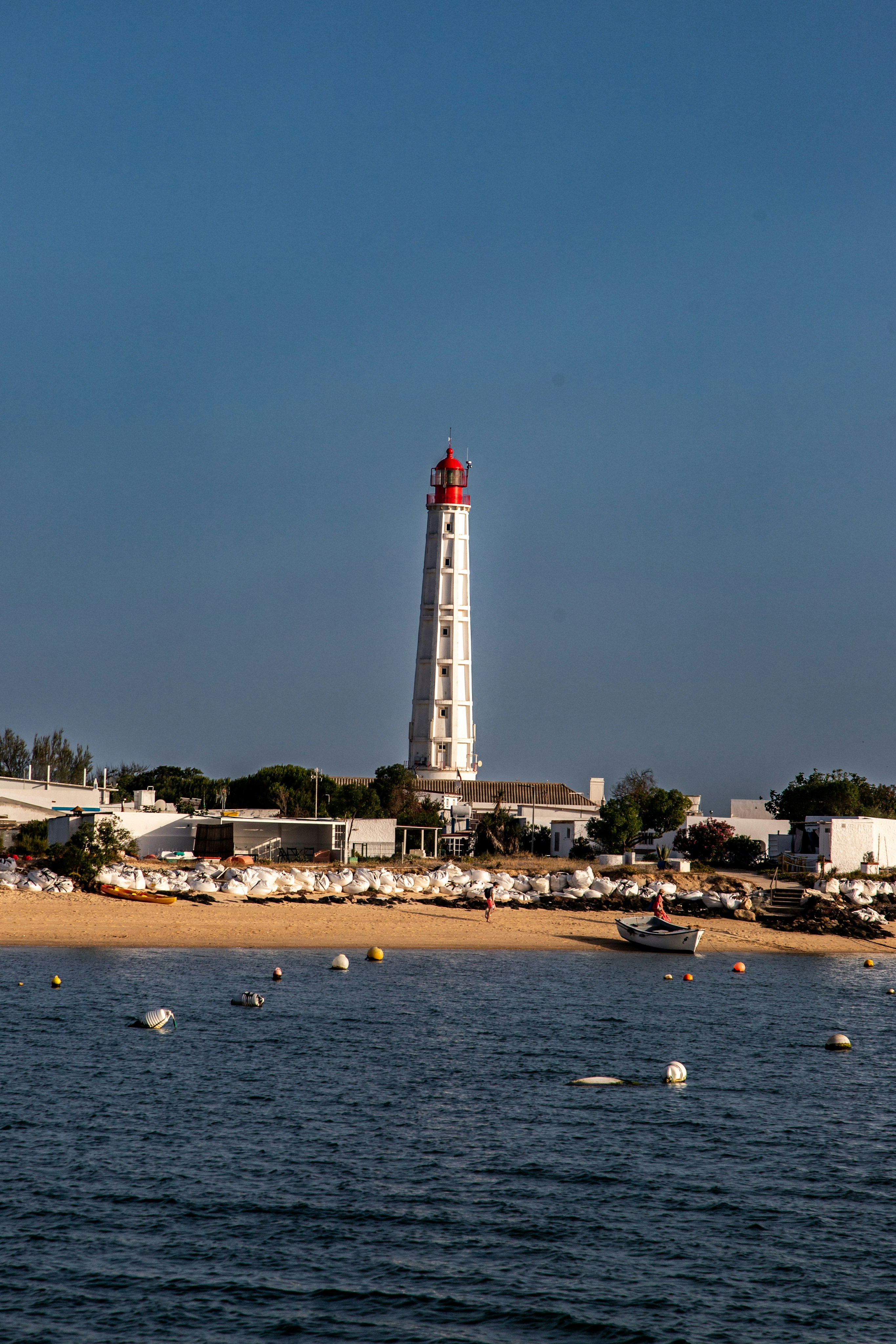 Coastal Beacon: A White Lighthouse Standing Against a Clear Sky