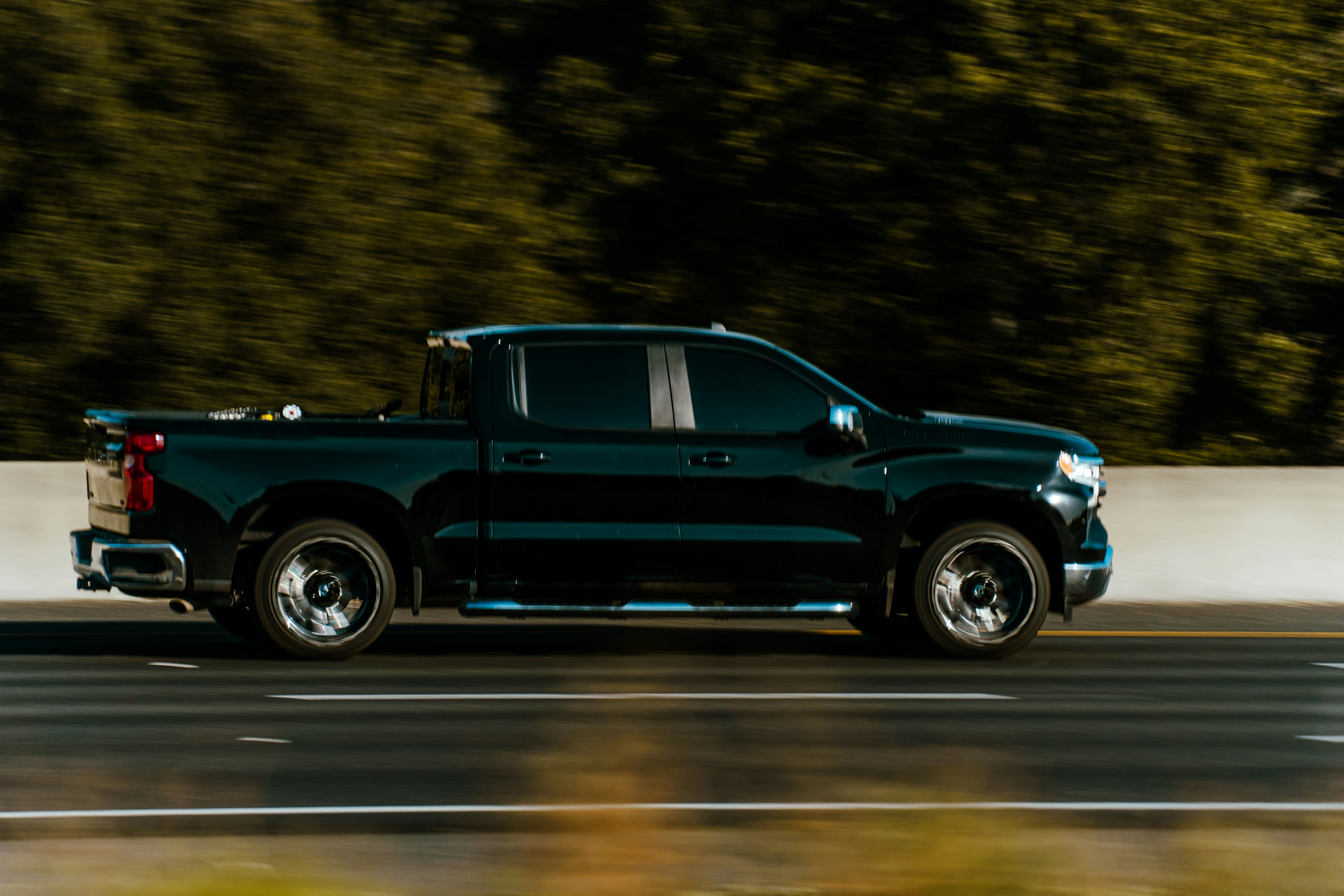 Dark Pickup in Motion: A Sleek Blue-Black Hauler Rushing Past