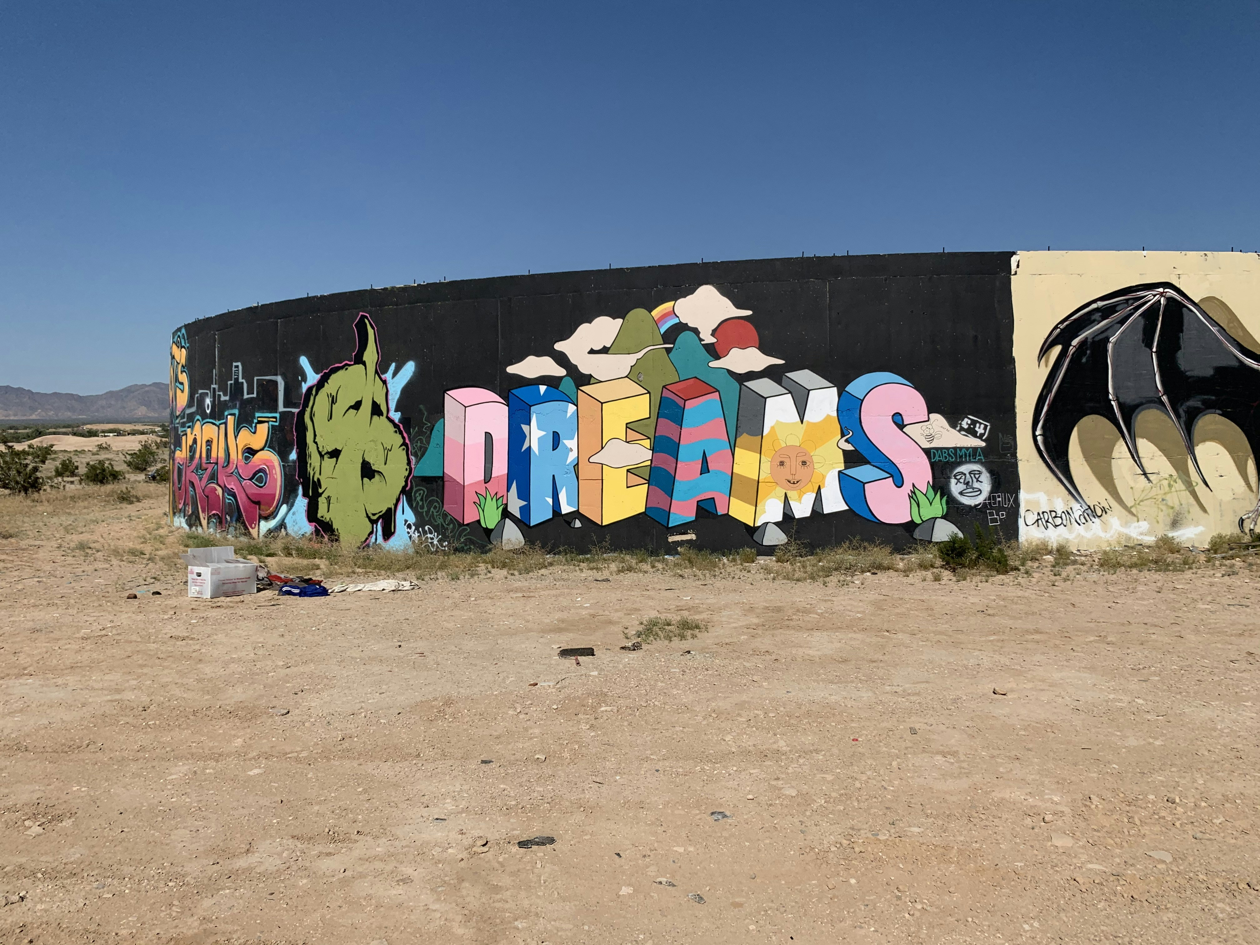 Desert Wall of Color: Graffiti Across a Sunlit Fenceline