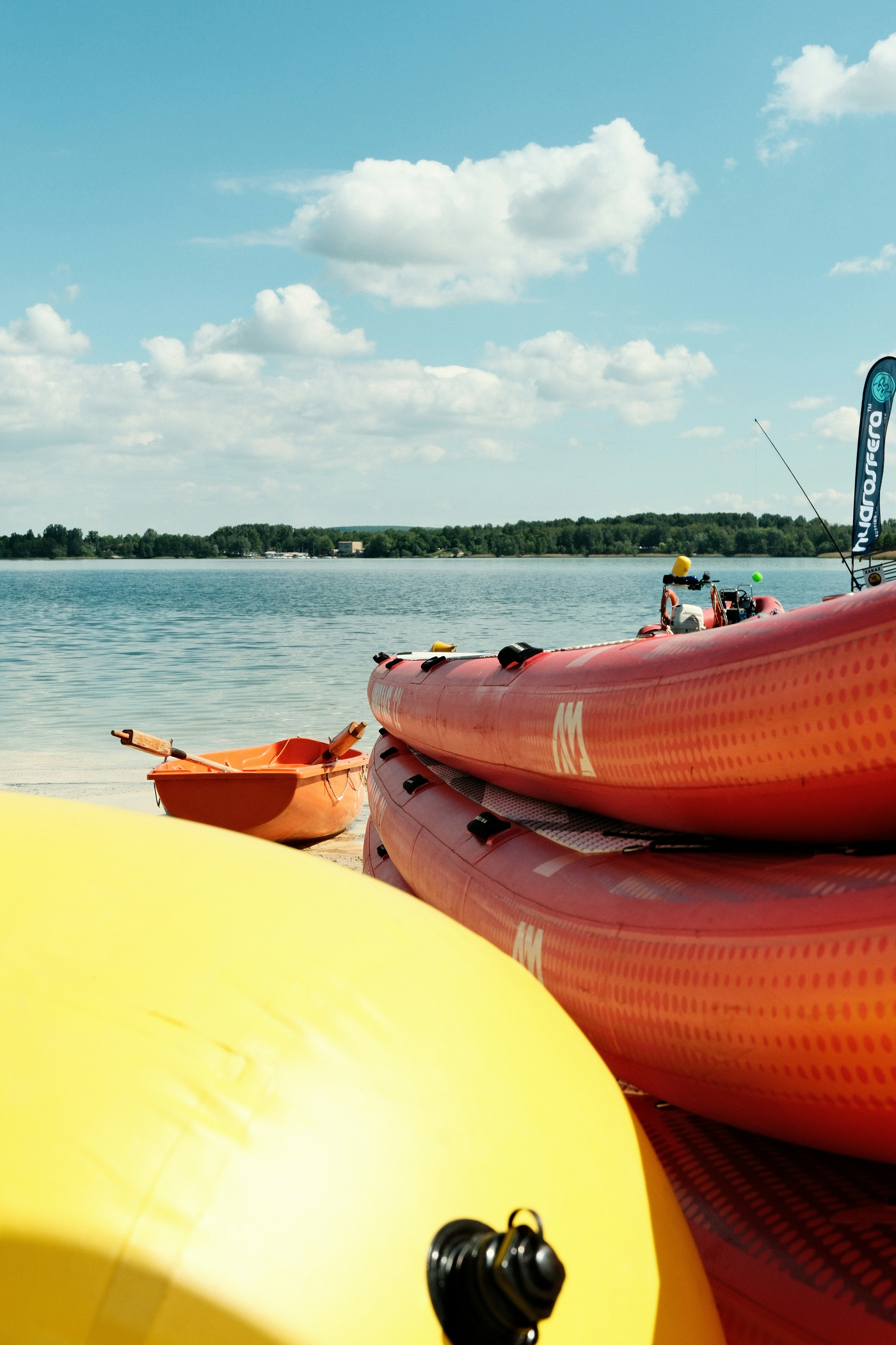 Racing on the Shore: Stacked Inflatable Boats by the Quiet Lake