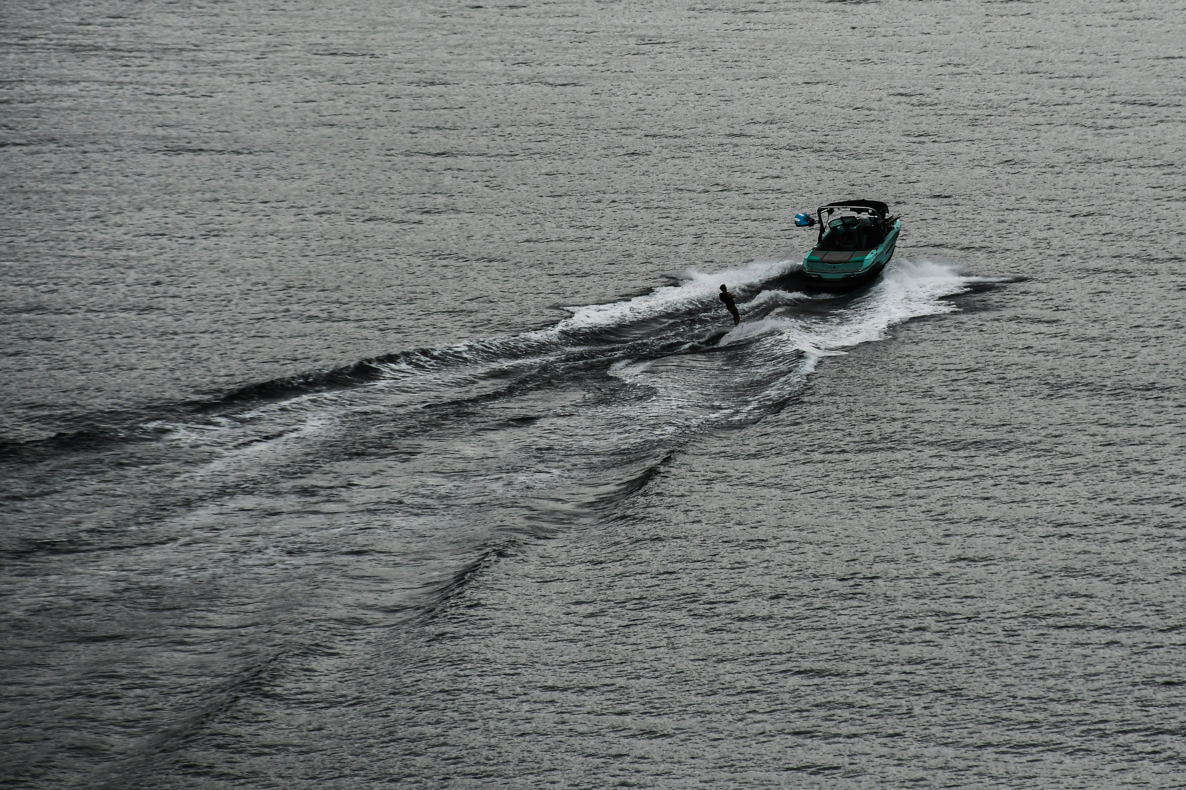 A lone speedboat carving a wake across gray horizons