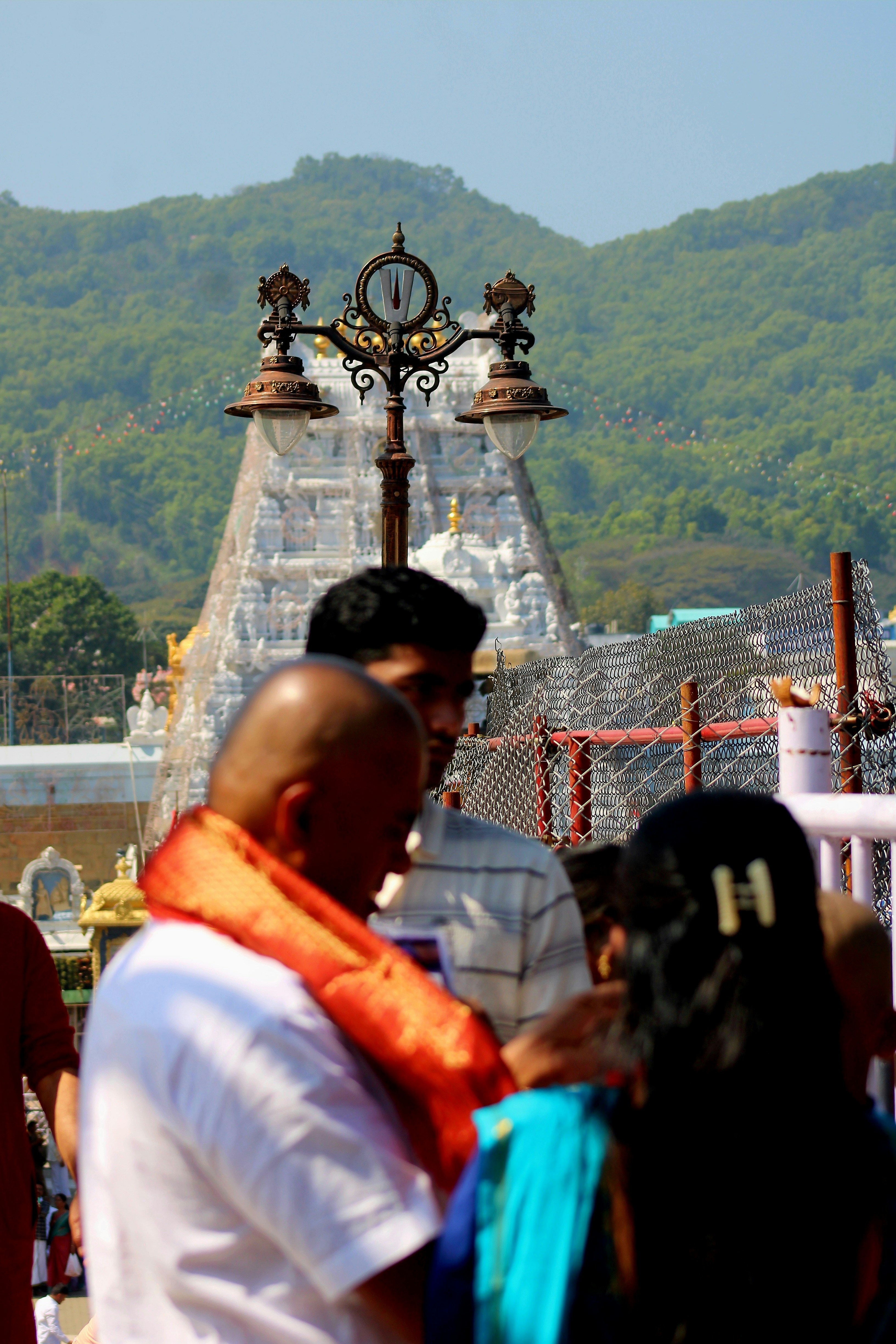 Crowd at a temple steps with ornate lamppost rising behind