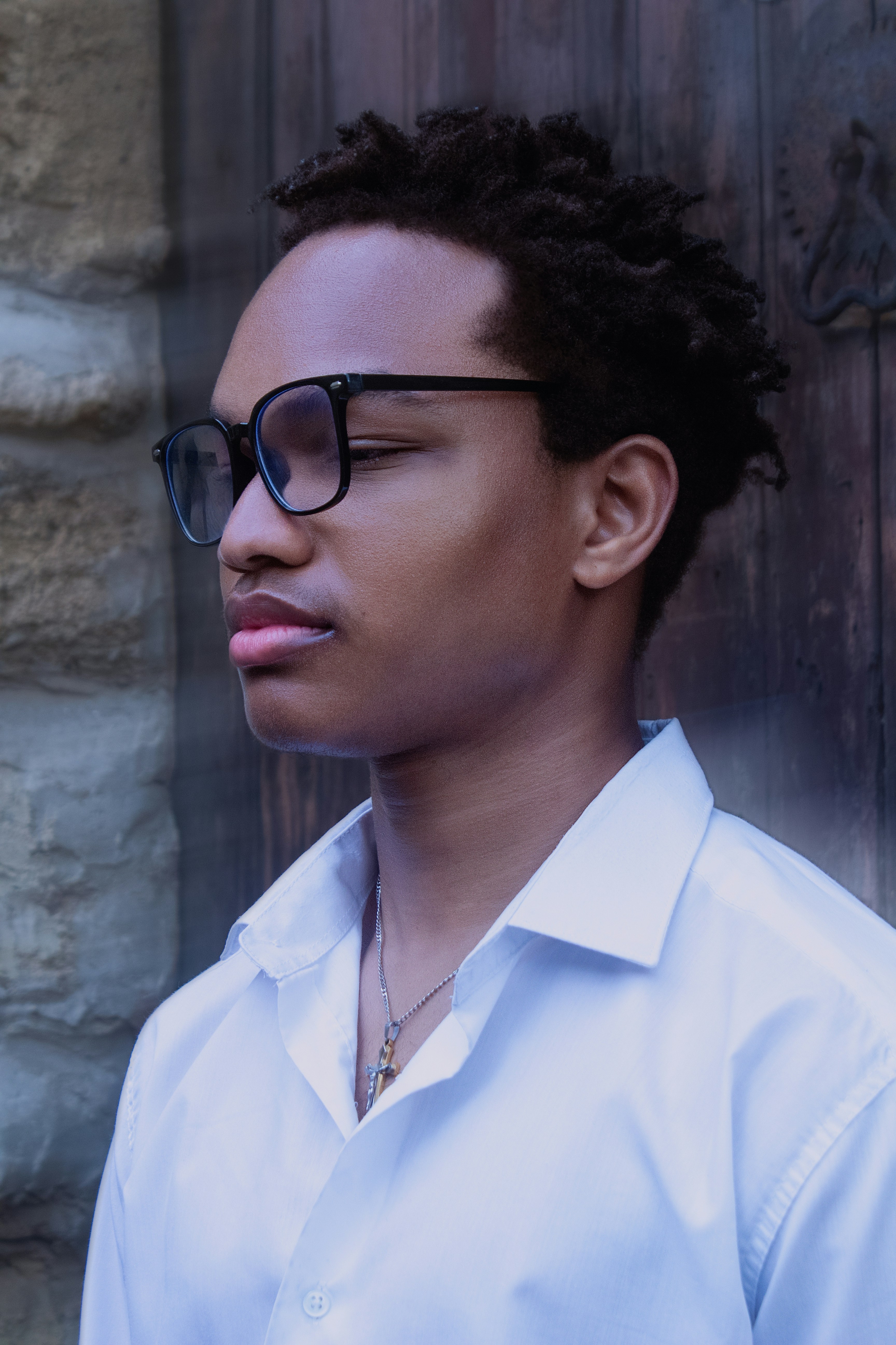 Glasses, Shadowed Gaze: A Quiet Portrait Against Weathered Wood