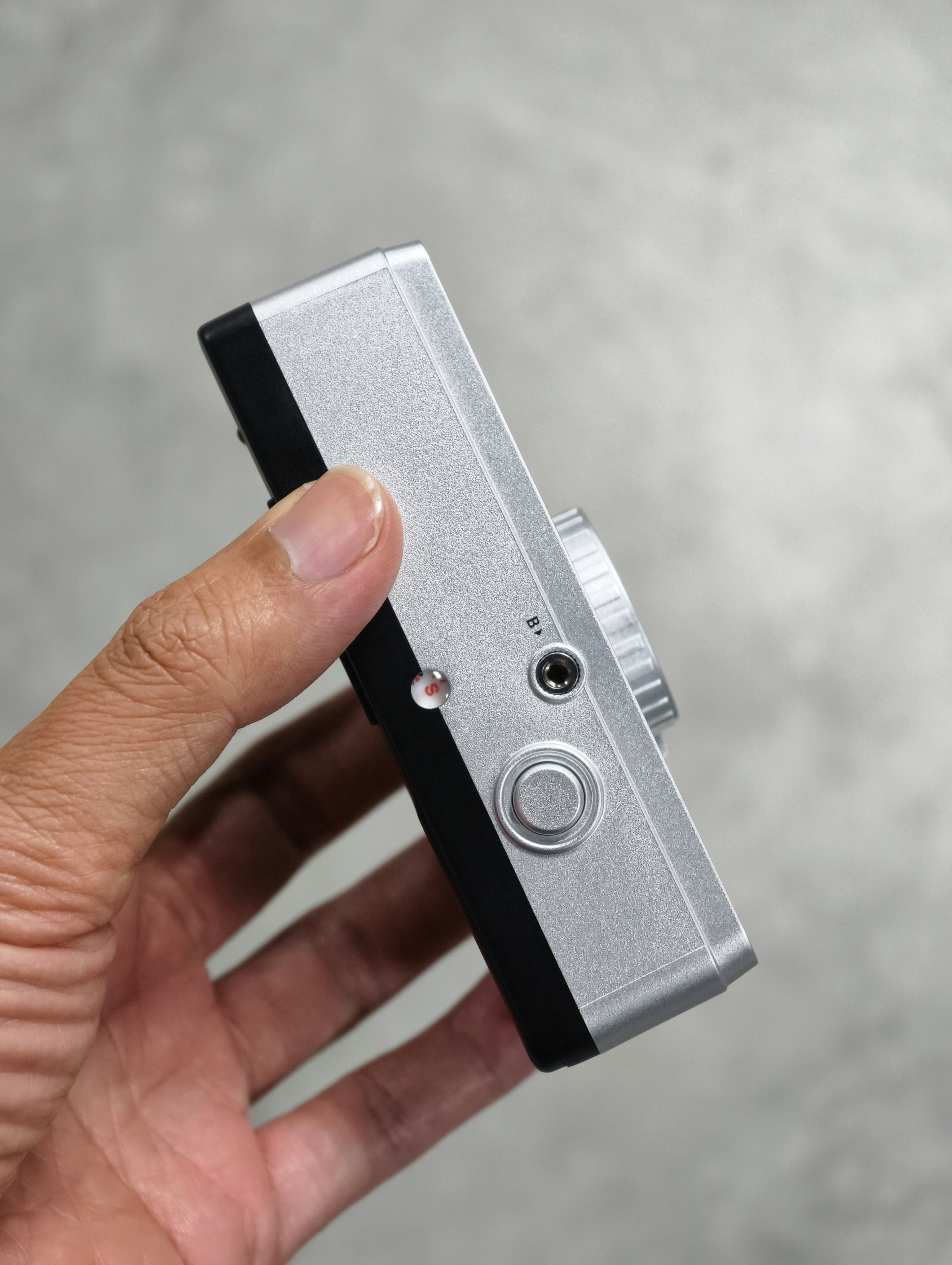 Hands-on Retro: A Metallic Pocket Camera Held Between Fingers