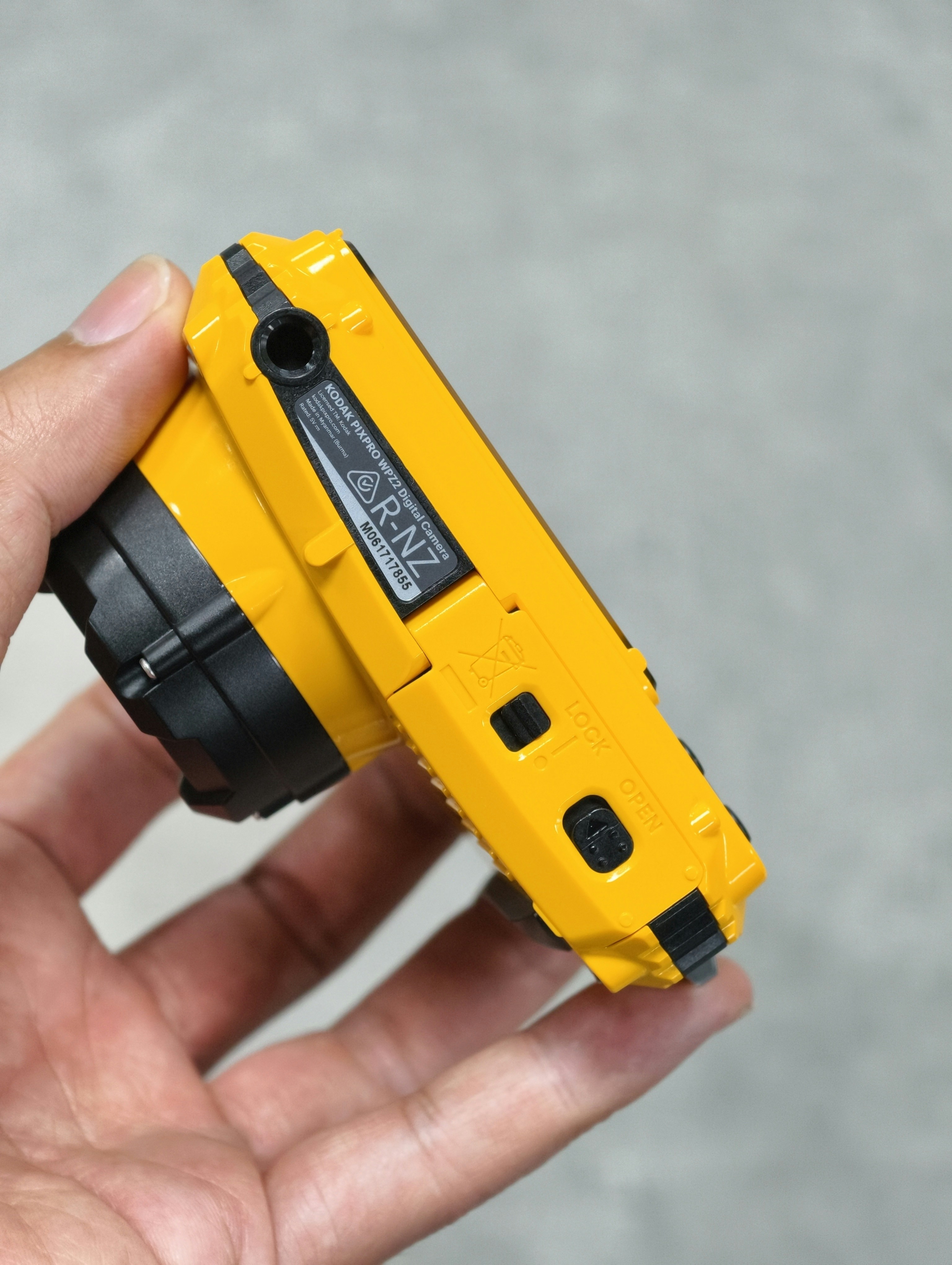 Bright yellow handheld tool model resting on a palm with a gray backdrop