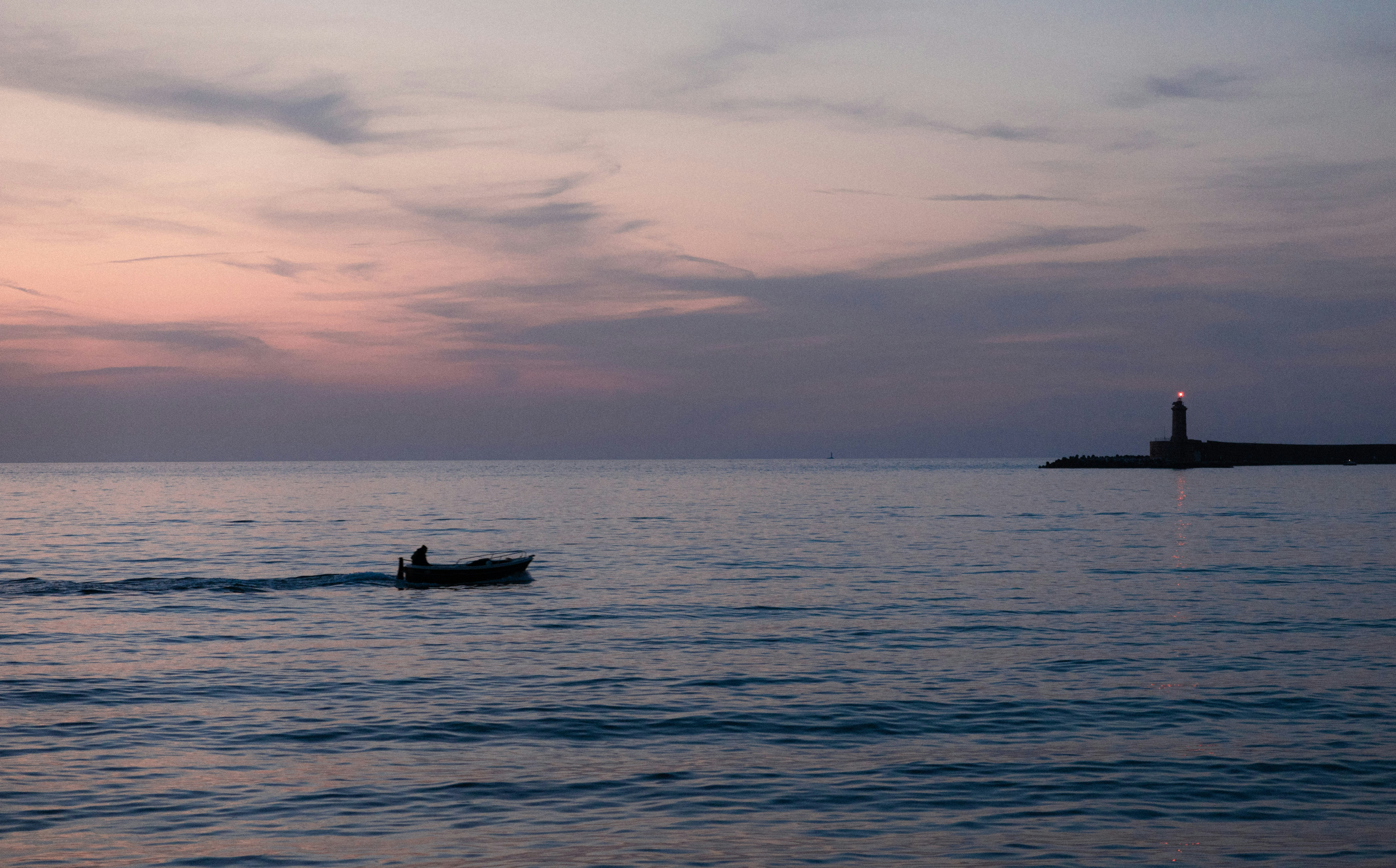 Dusk over the Quiet Sea: Boat, Horizon, and Lighthouse