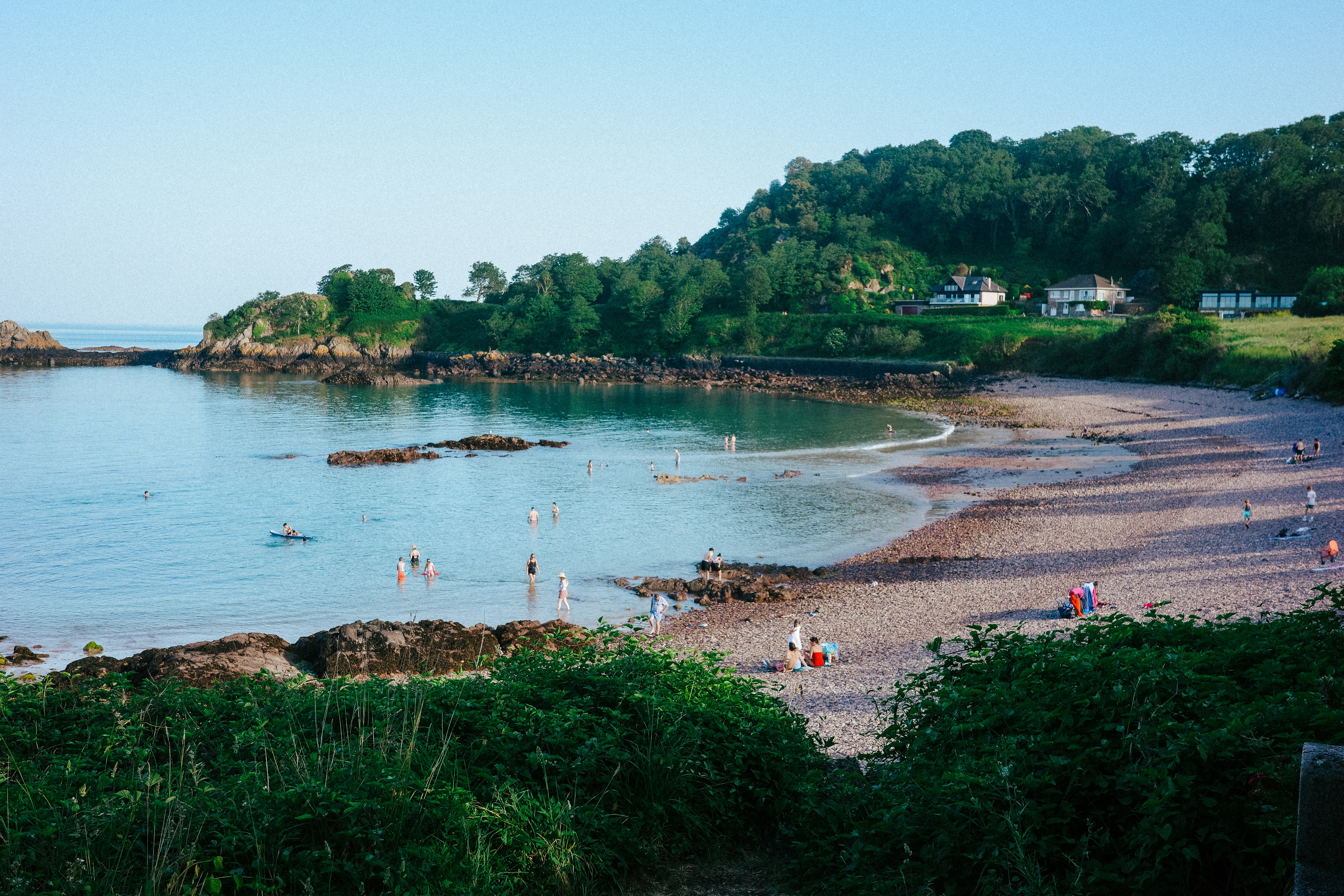 Coastal Cove: Sunlit Beach Toward Distant Homes