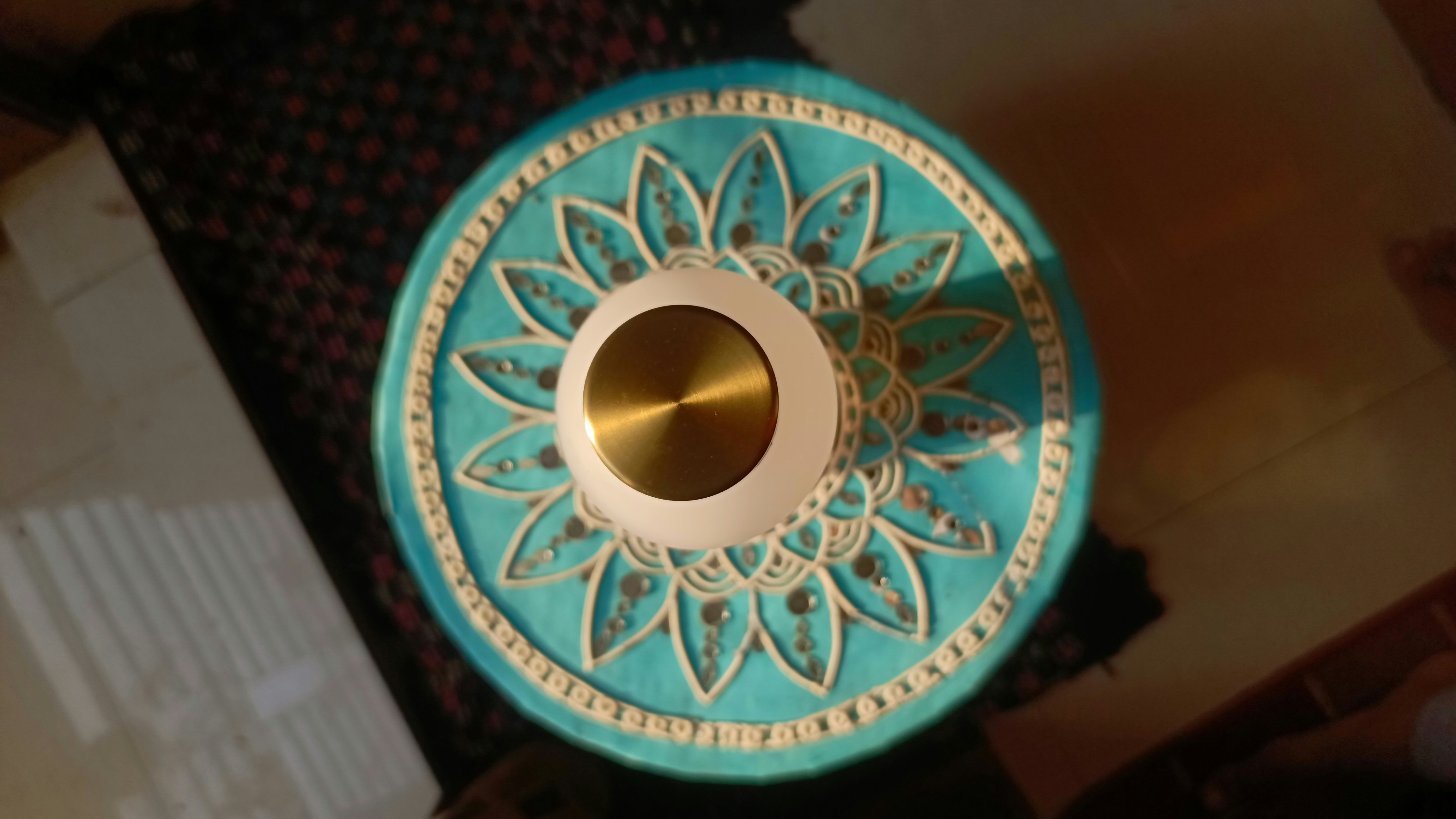 Vibrant teal mandala glow from a brass-knob centerpiece