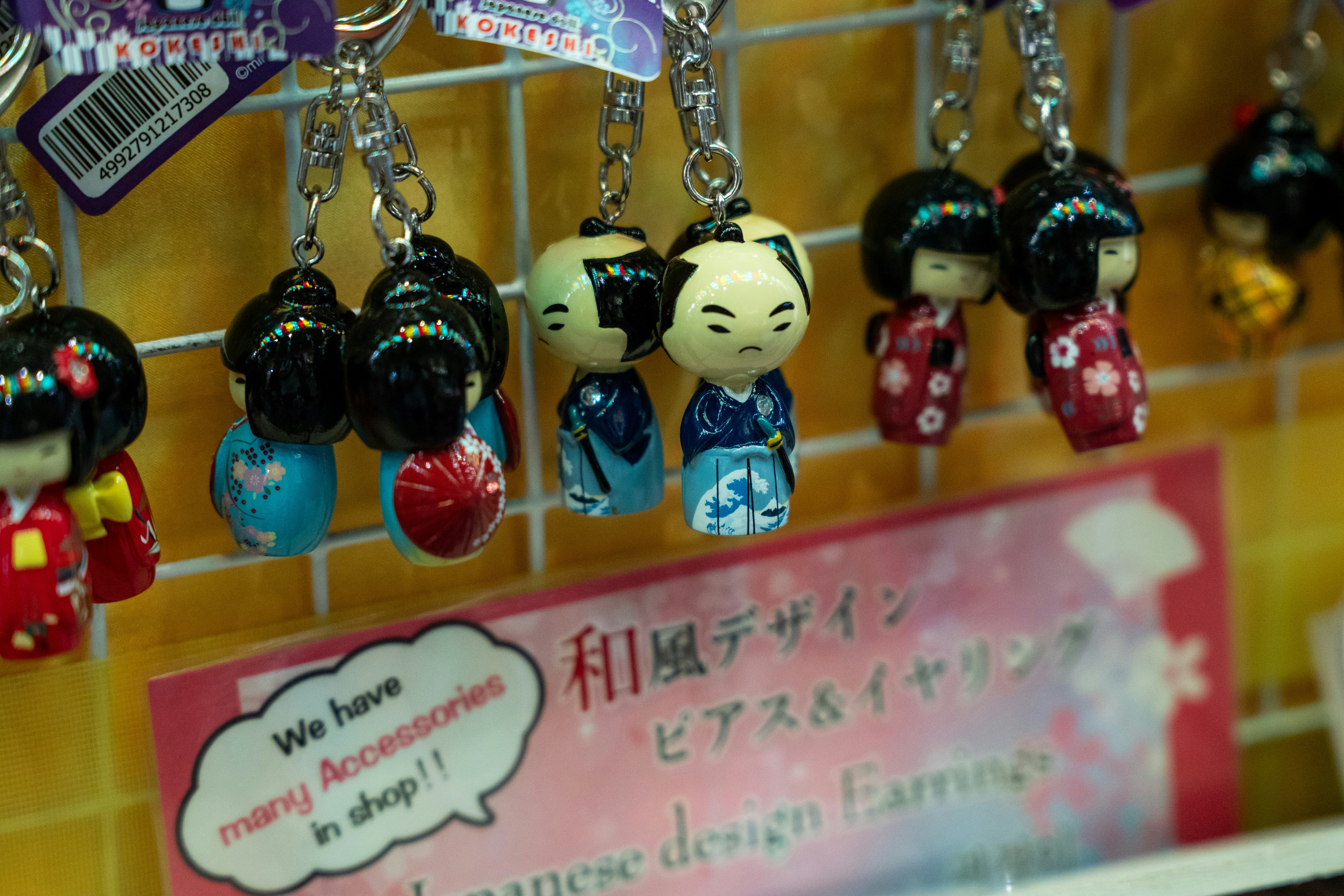 Tiny Japanese Kokeshi Earrings Dangle Above a Bright Display