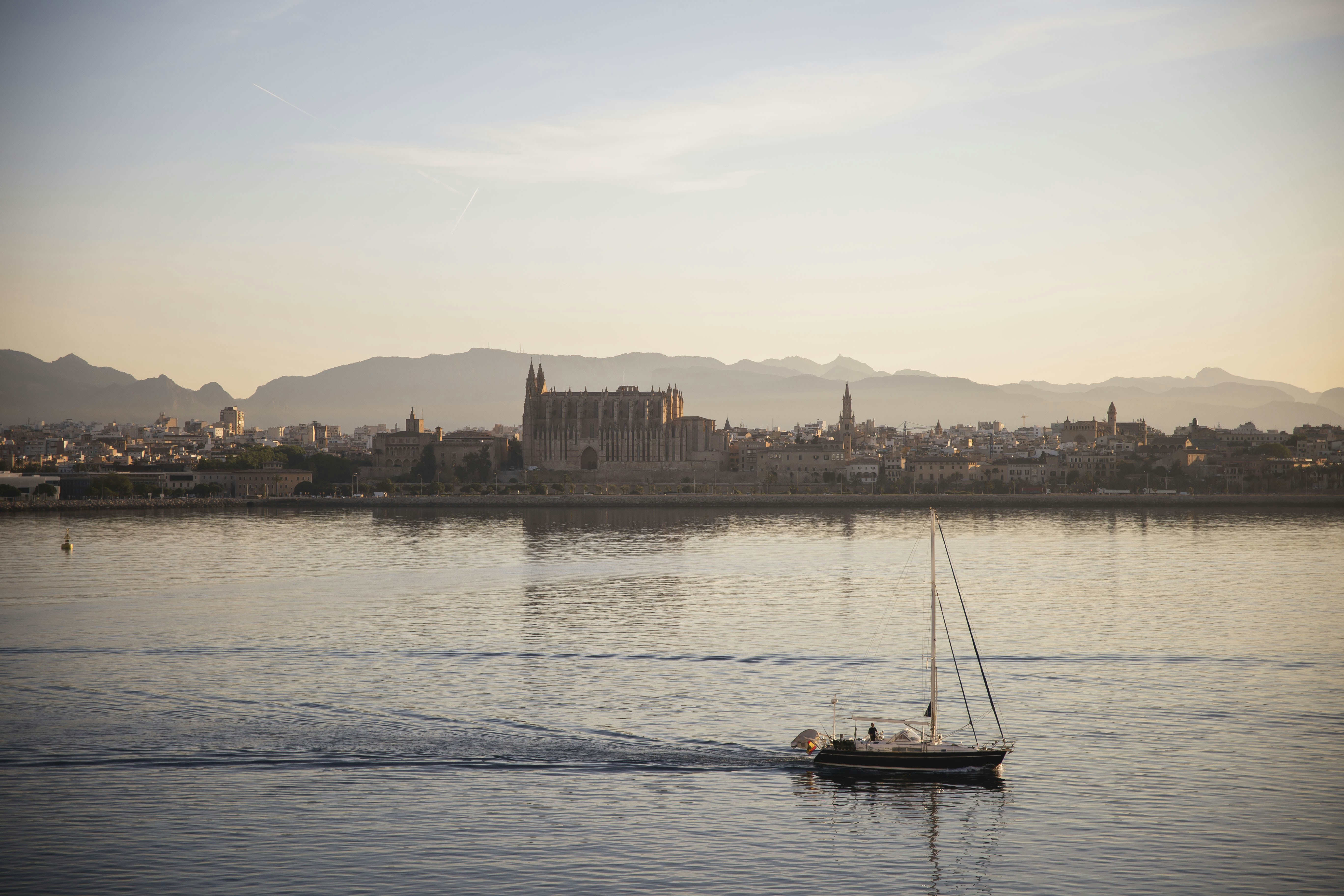 Calm Harbor Crossing: A Sailboat Traces a Quiet Line Across the Cityscape