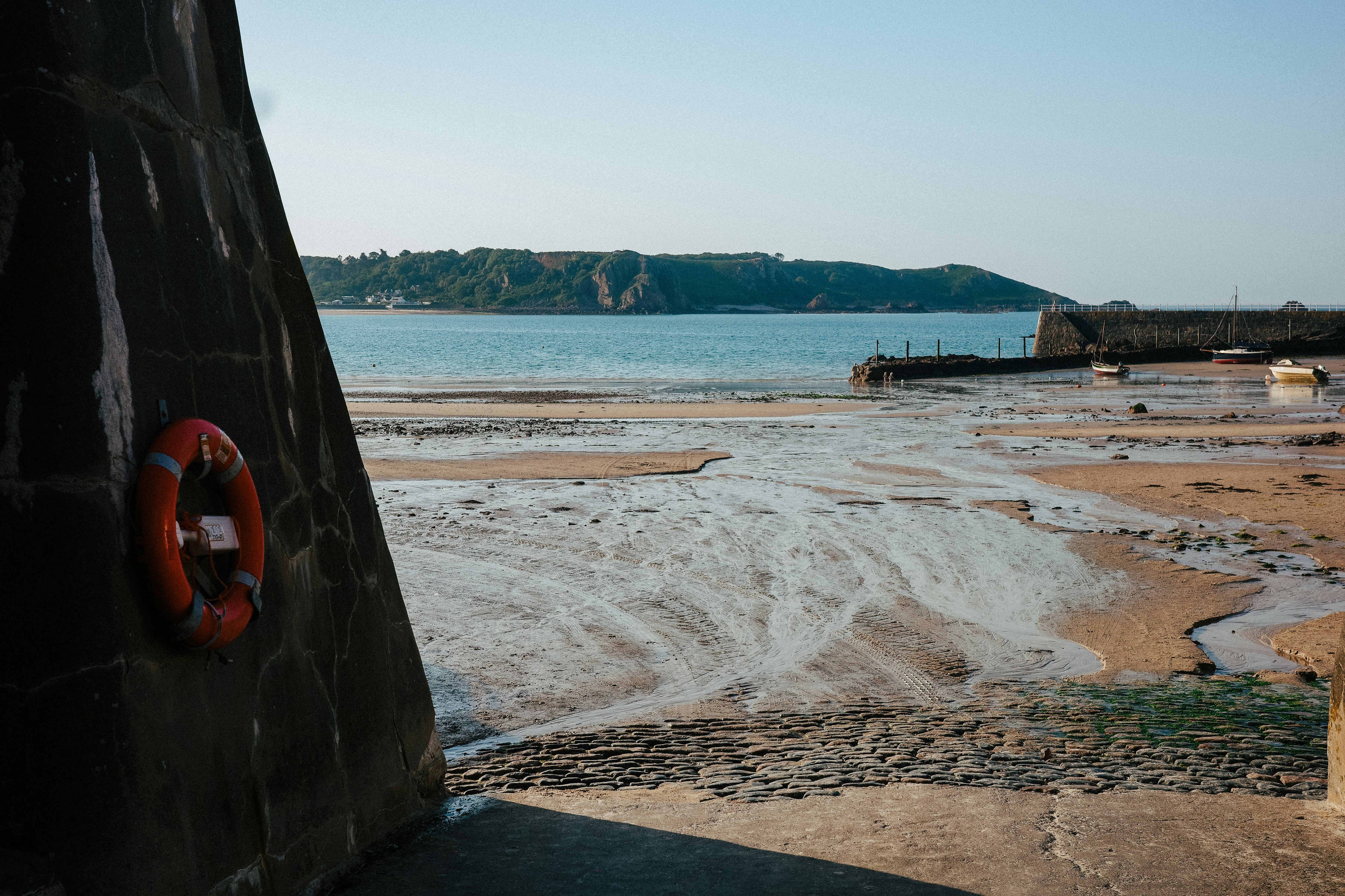 Harbor Shadow: A Lifebuoy Grasped by Concrete Edges Over Quiet Tide