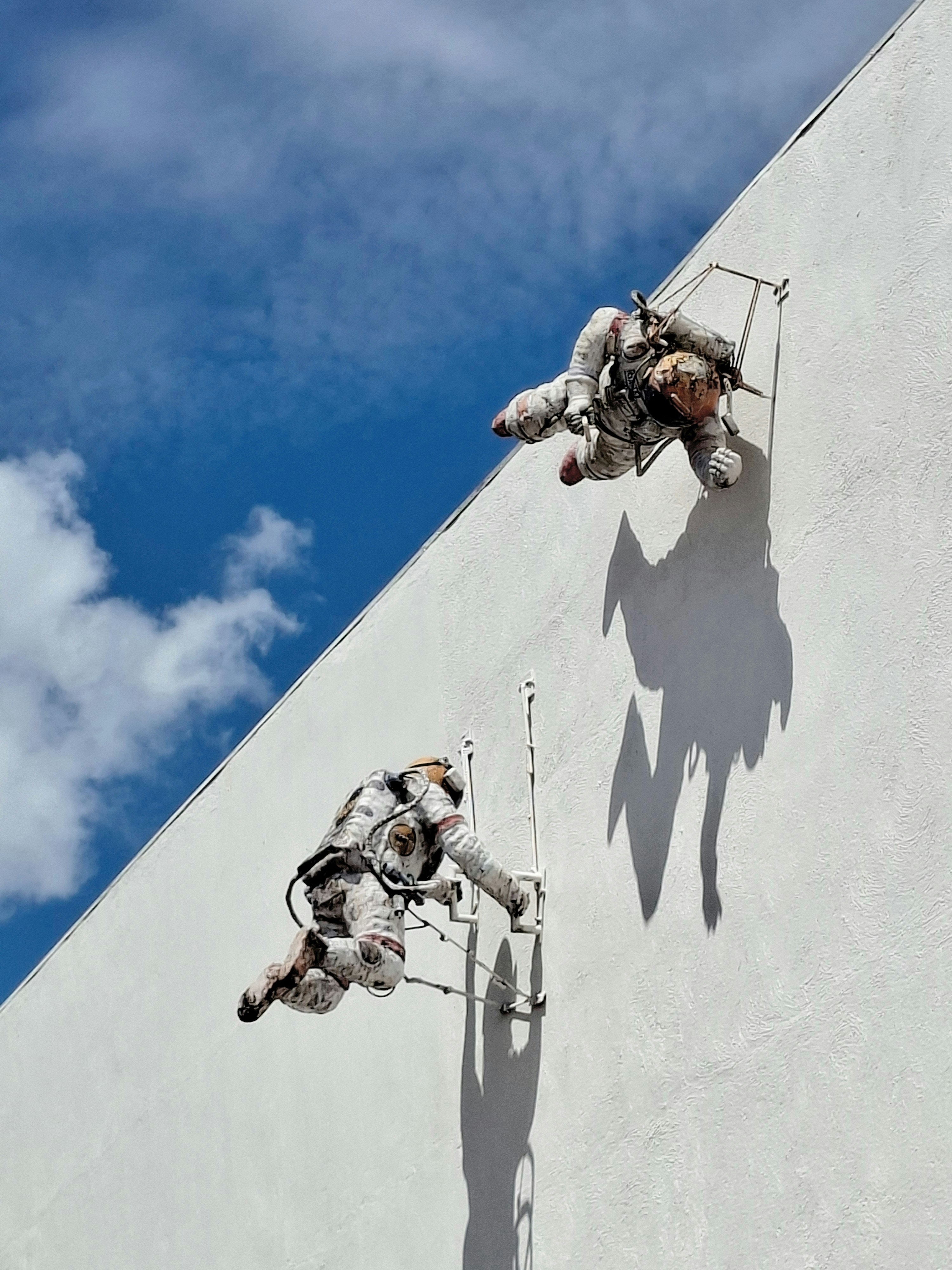 Climbers on a White Facade: Aerial Distant Duo in Space-Suited Solitude