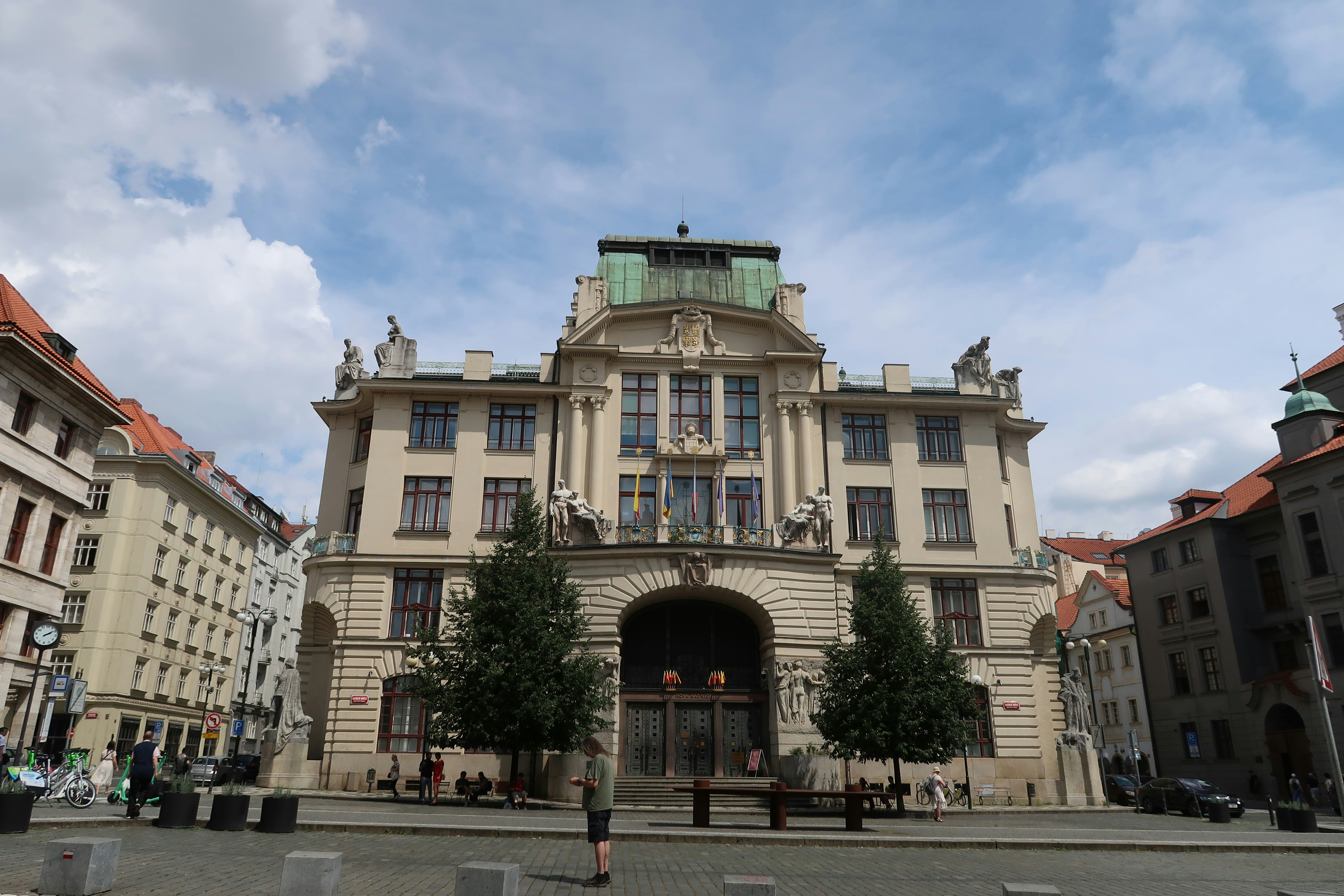 Entrance of a grand historic town hall framed by trees and pedestrians