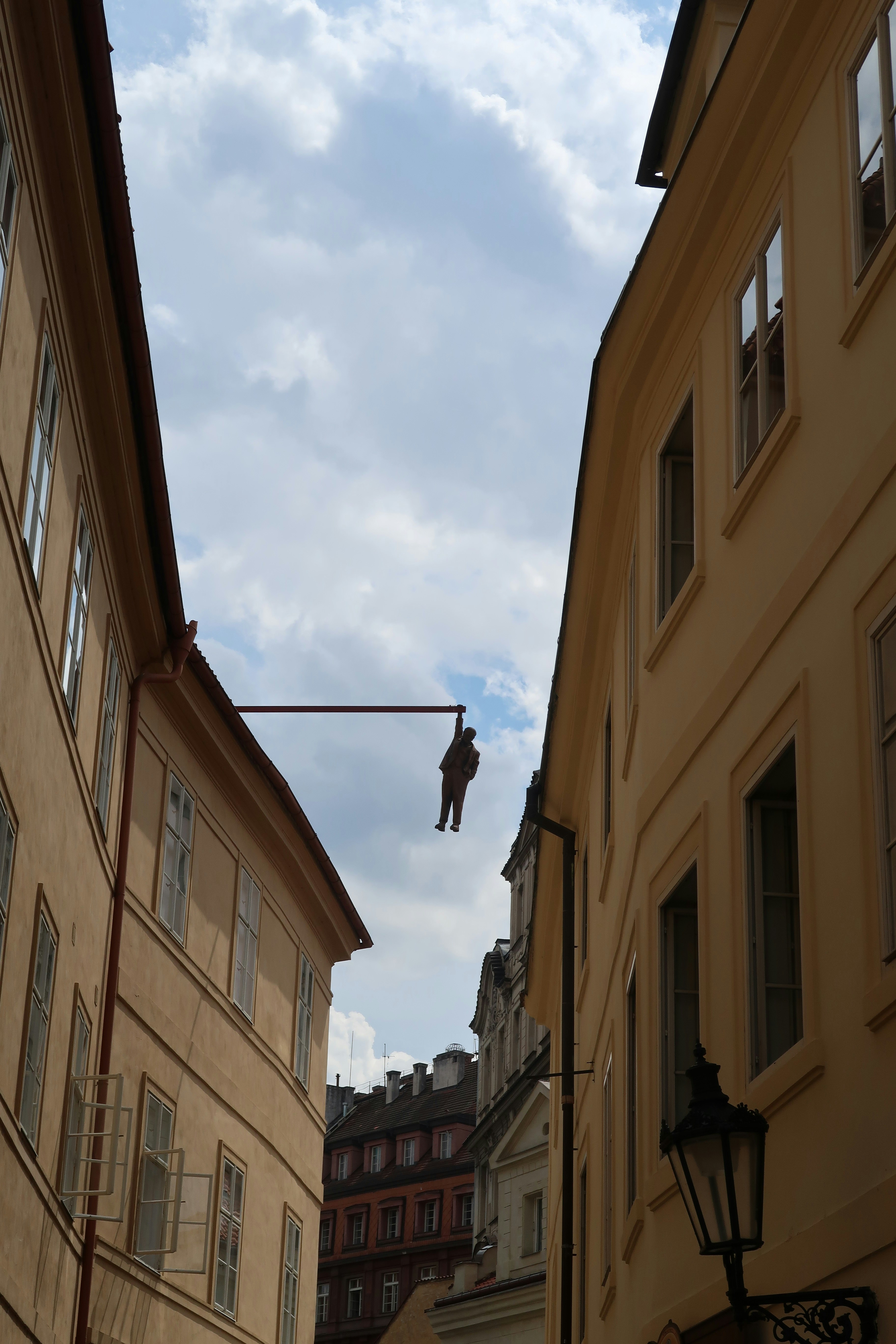 A Narrow Street Tragedy Afloat: Suspended Figure Between Sunlit Facades