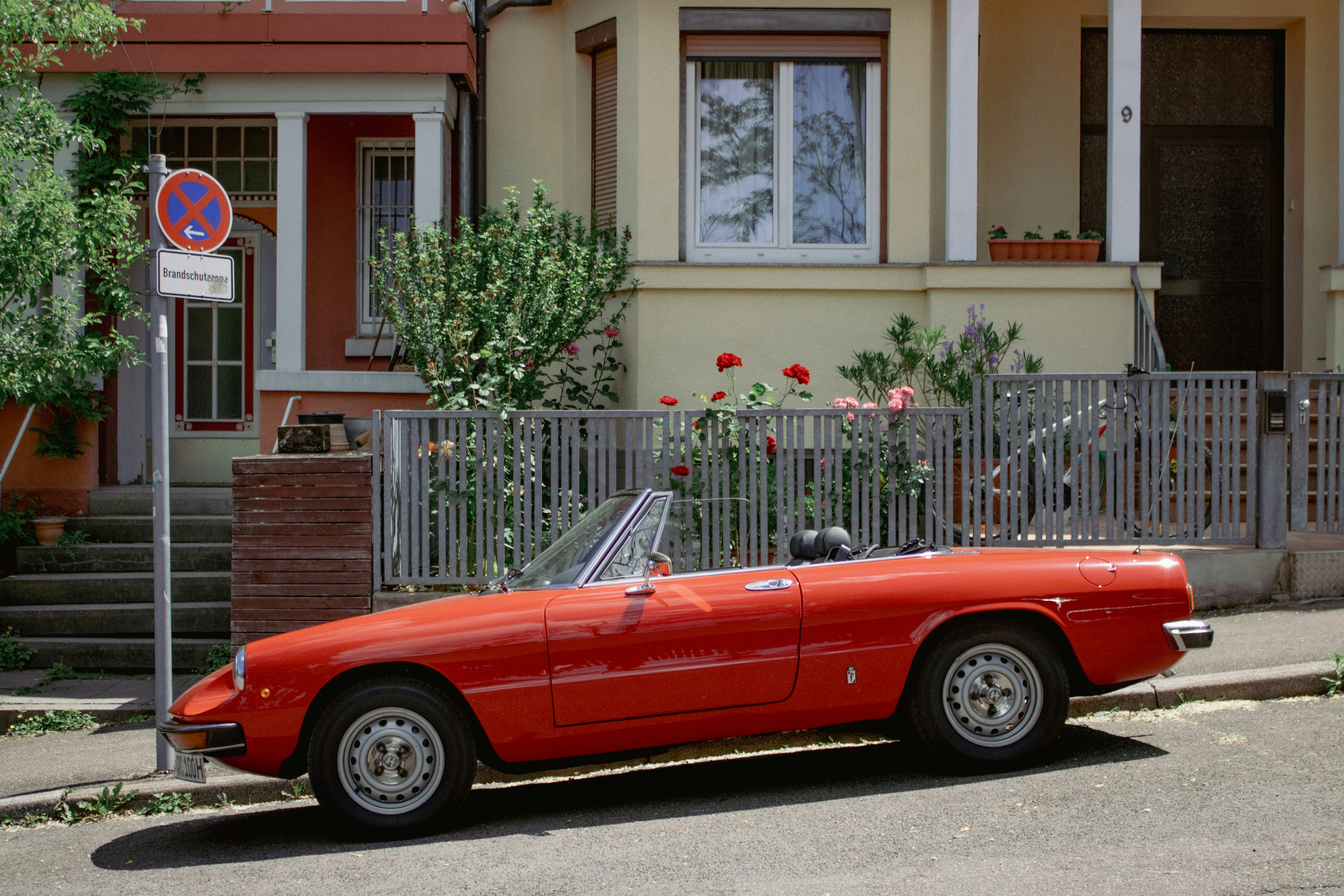 Red Classic Convertible Anchored by a Quiet Urban Street