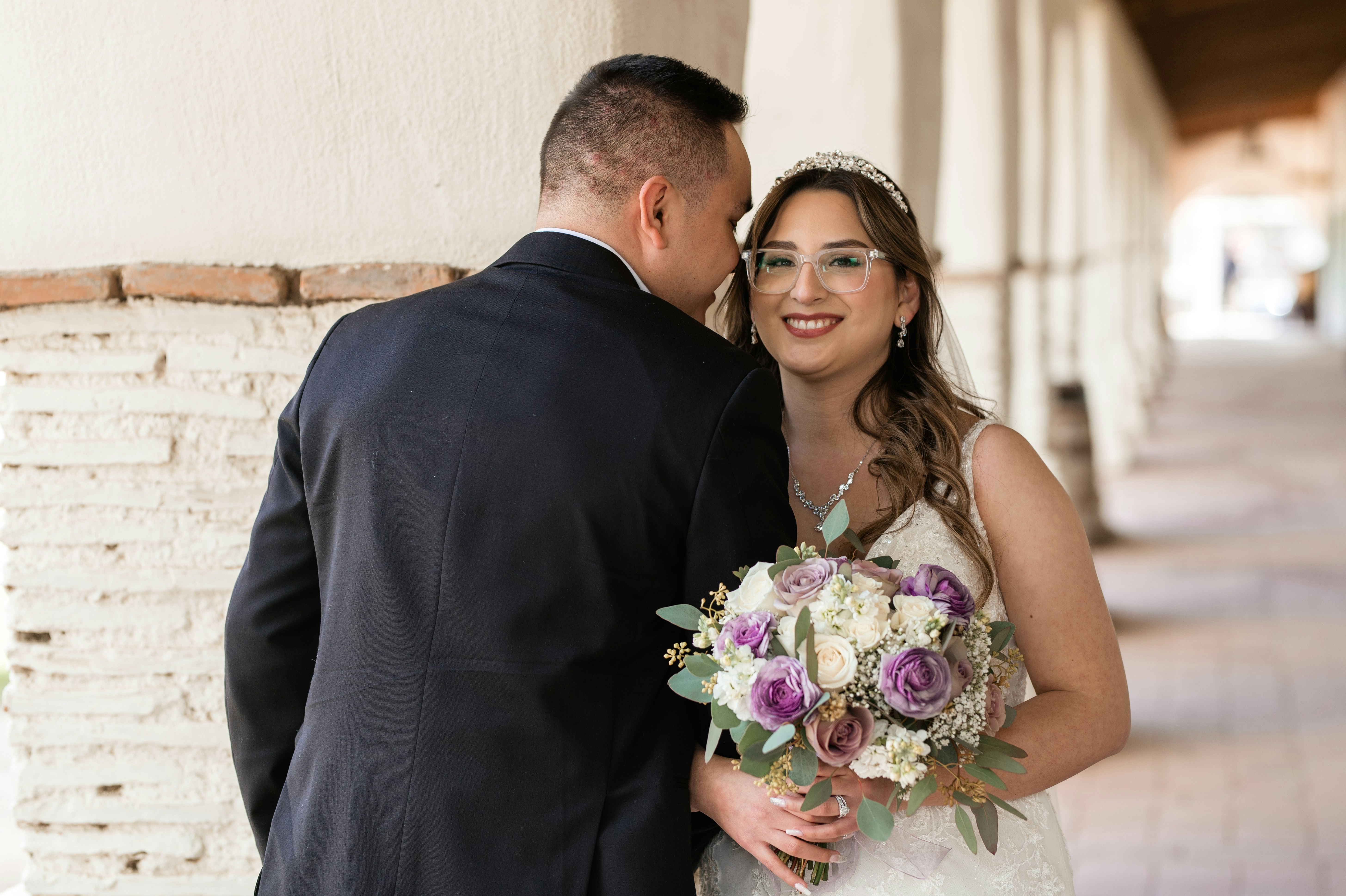 A smiling bride and groom under an archway.