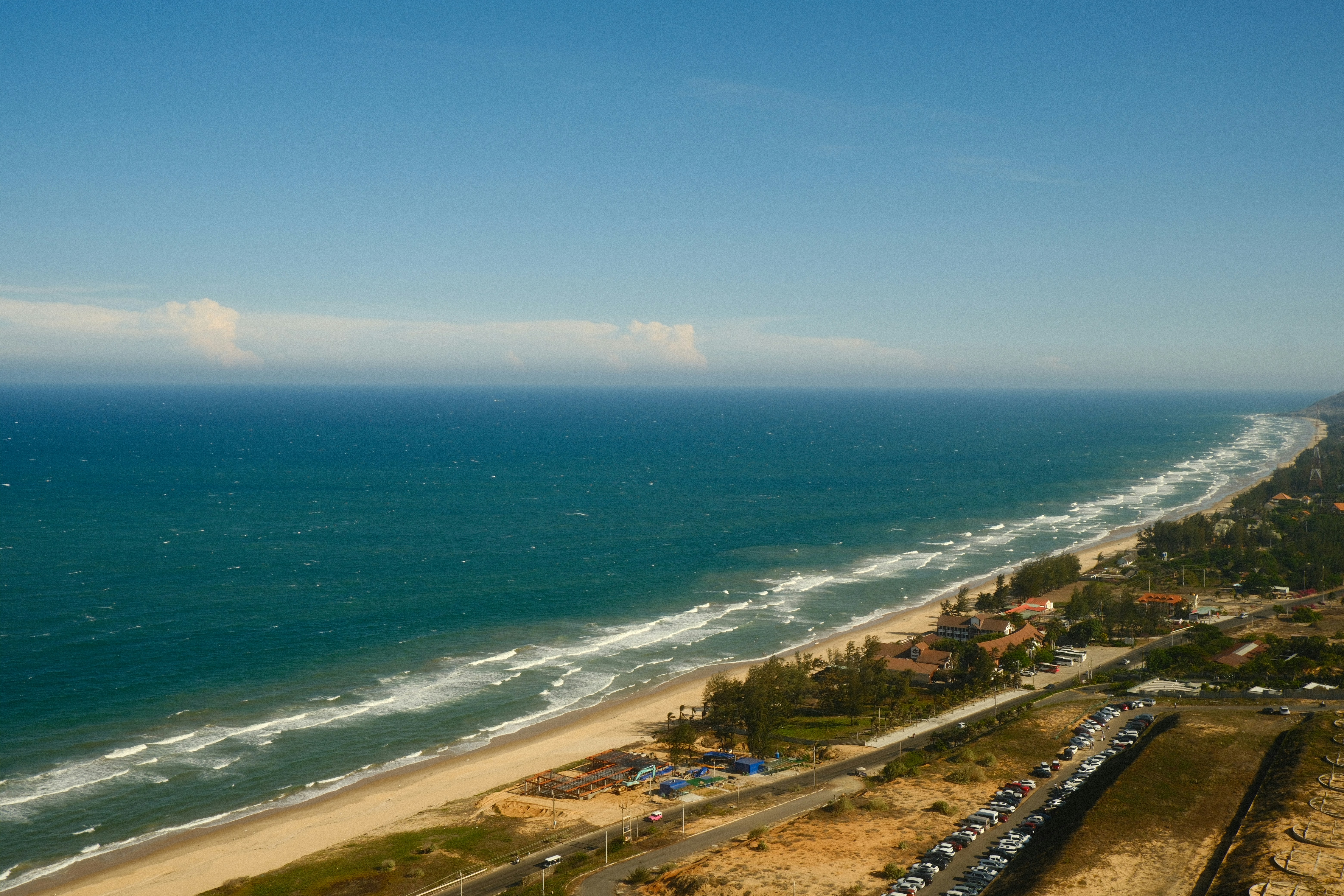 Sunlit Coastline: Aerial Vista of Beachfront, Road, and Dunes