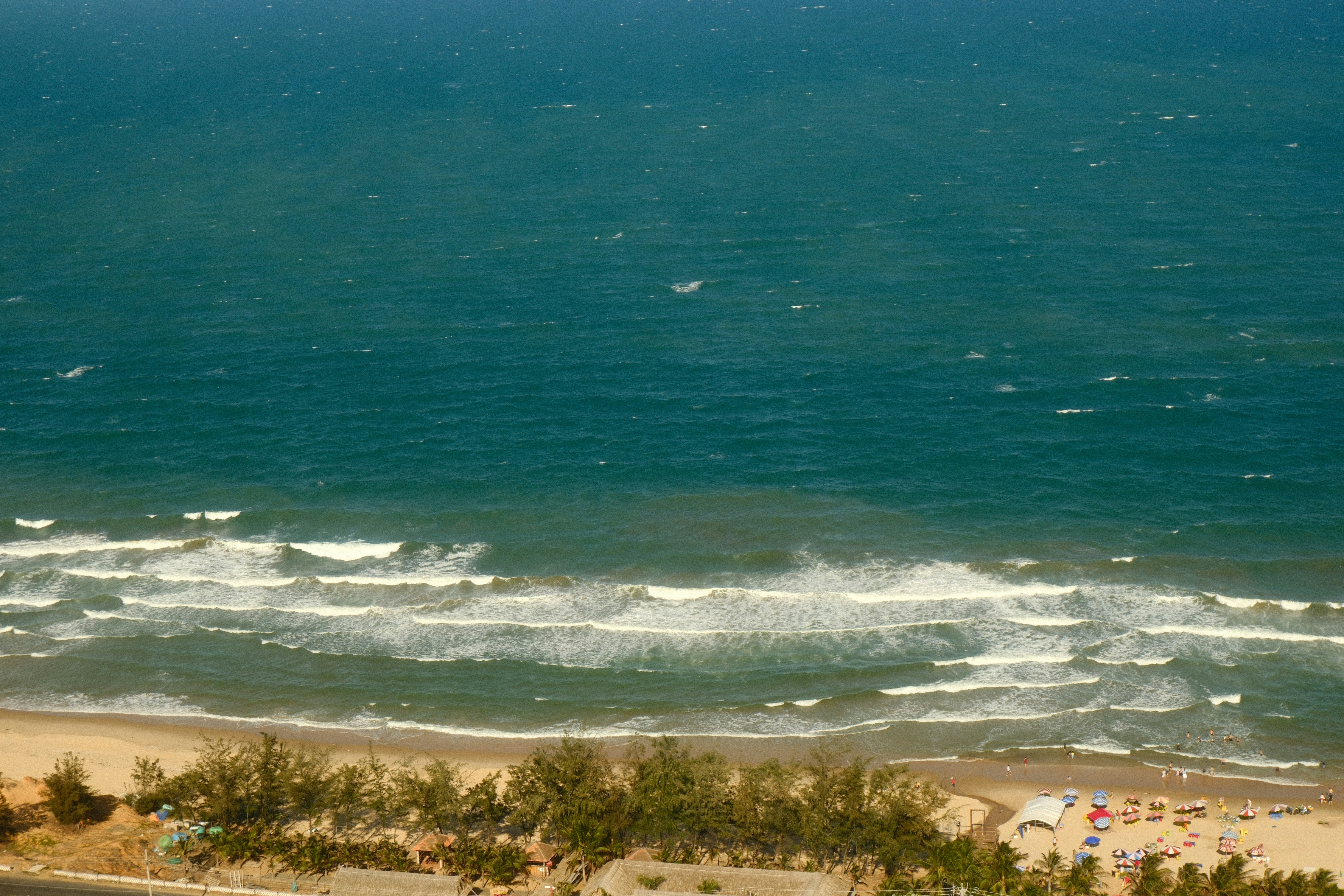 Sunlit shoreline: Aerial view of beach and rolling surf