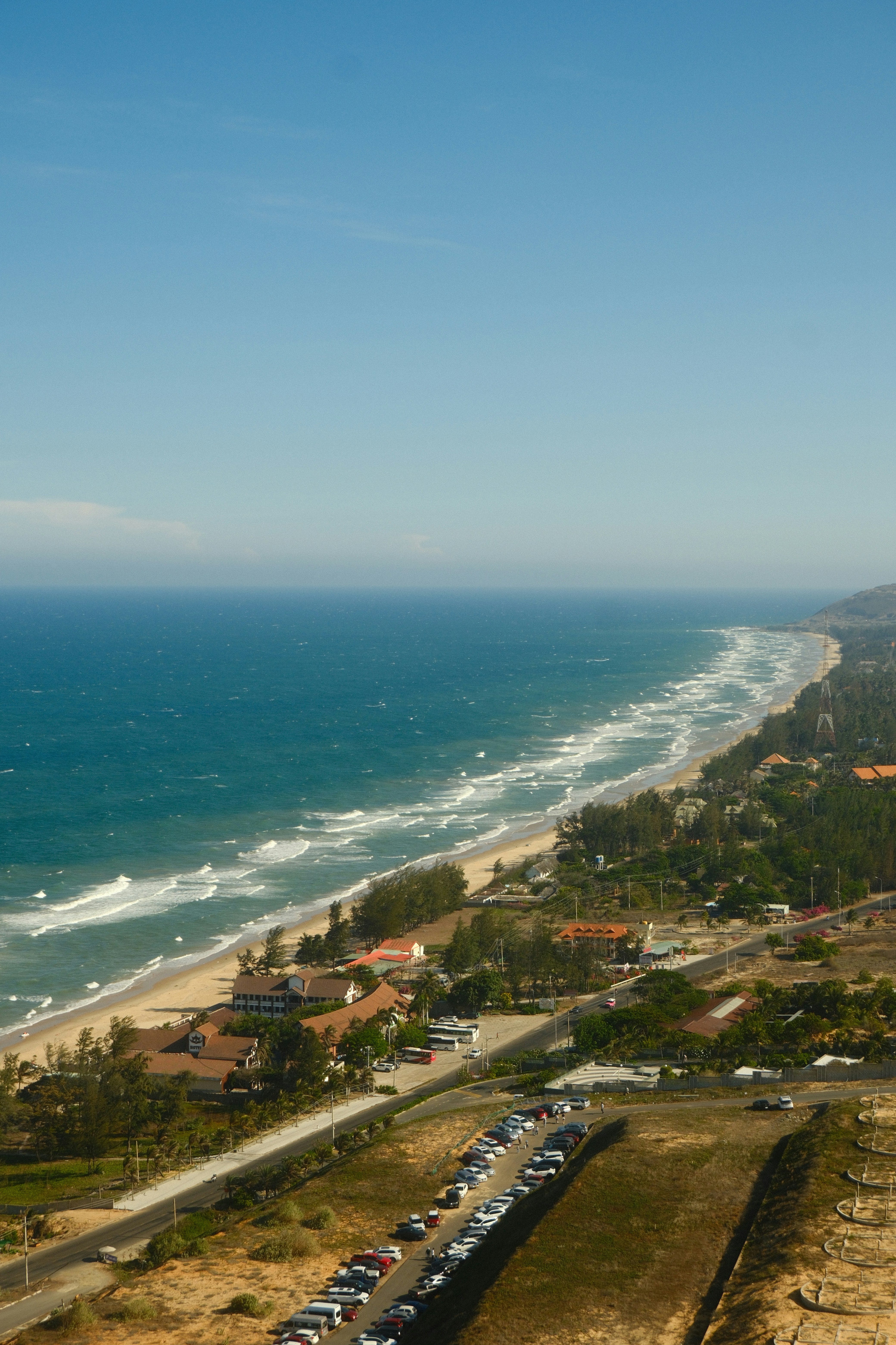 Coastline Corridor: Aerial Roadside Village Along a Blue Horizon