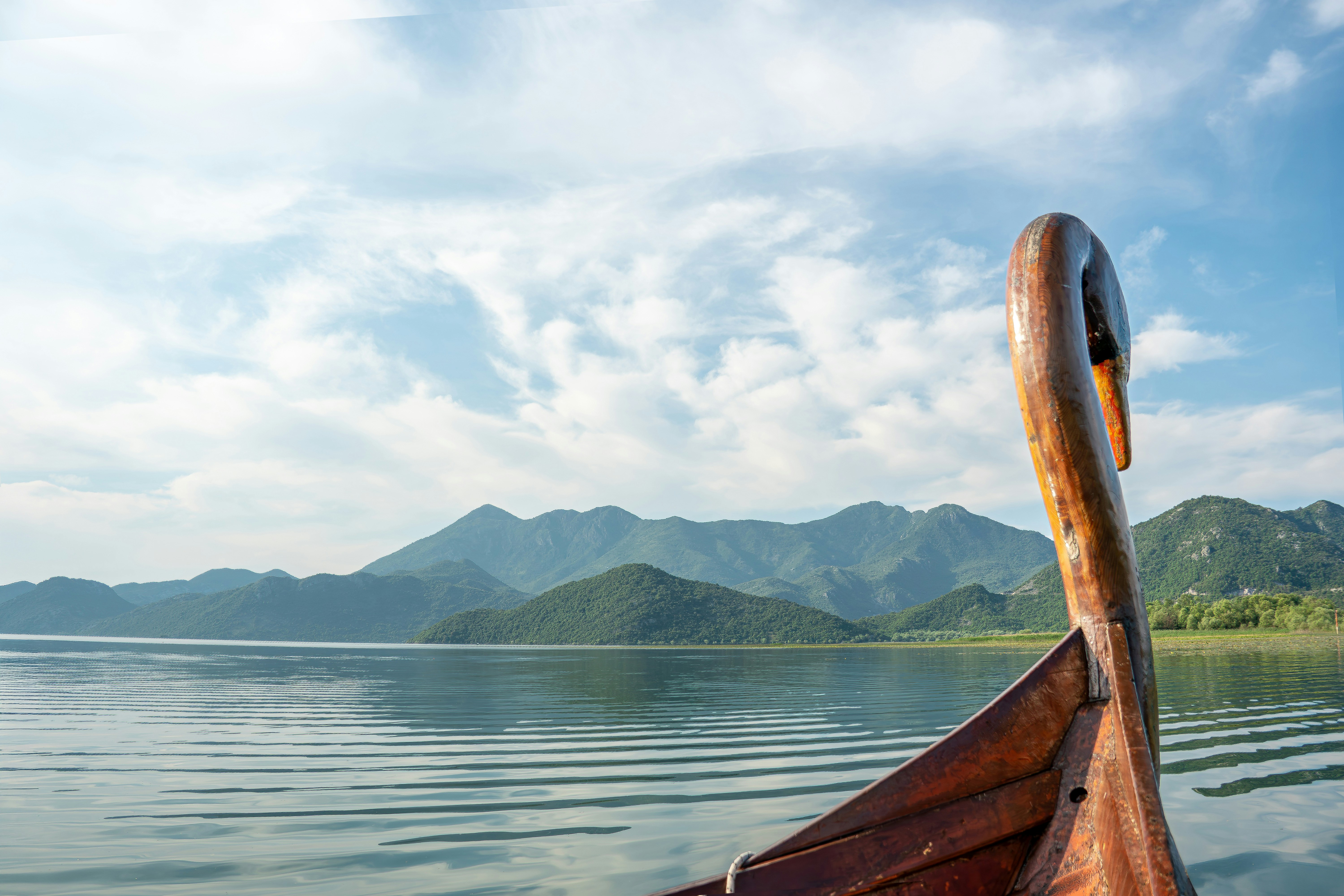 Bow of a Wooden Vessel Meeting a Serene Lake and Distant Mountains