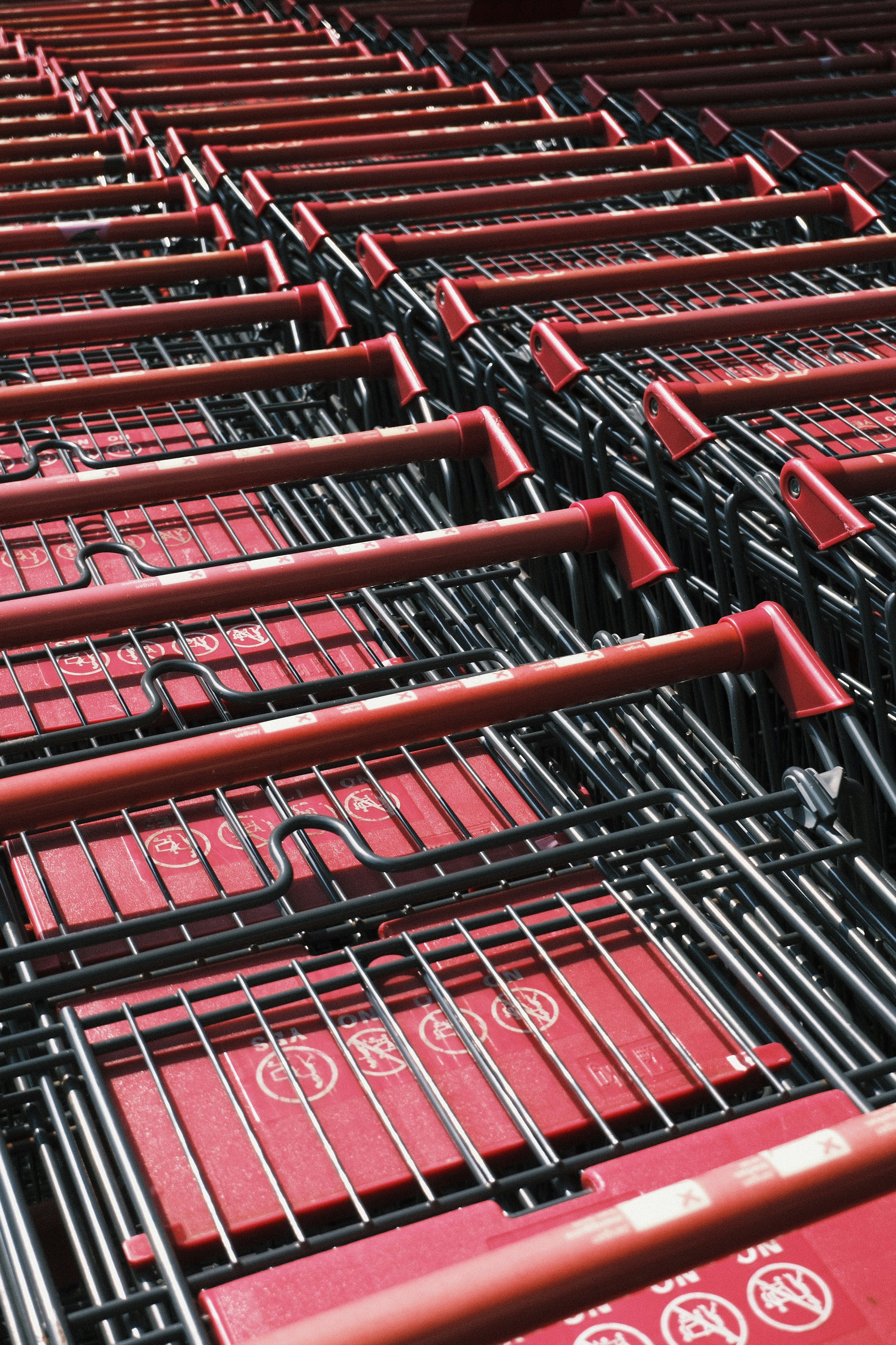Stacked shopping carts with red handles and bases.
