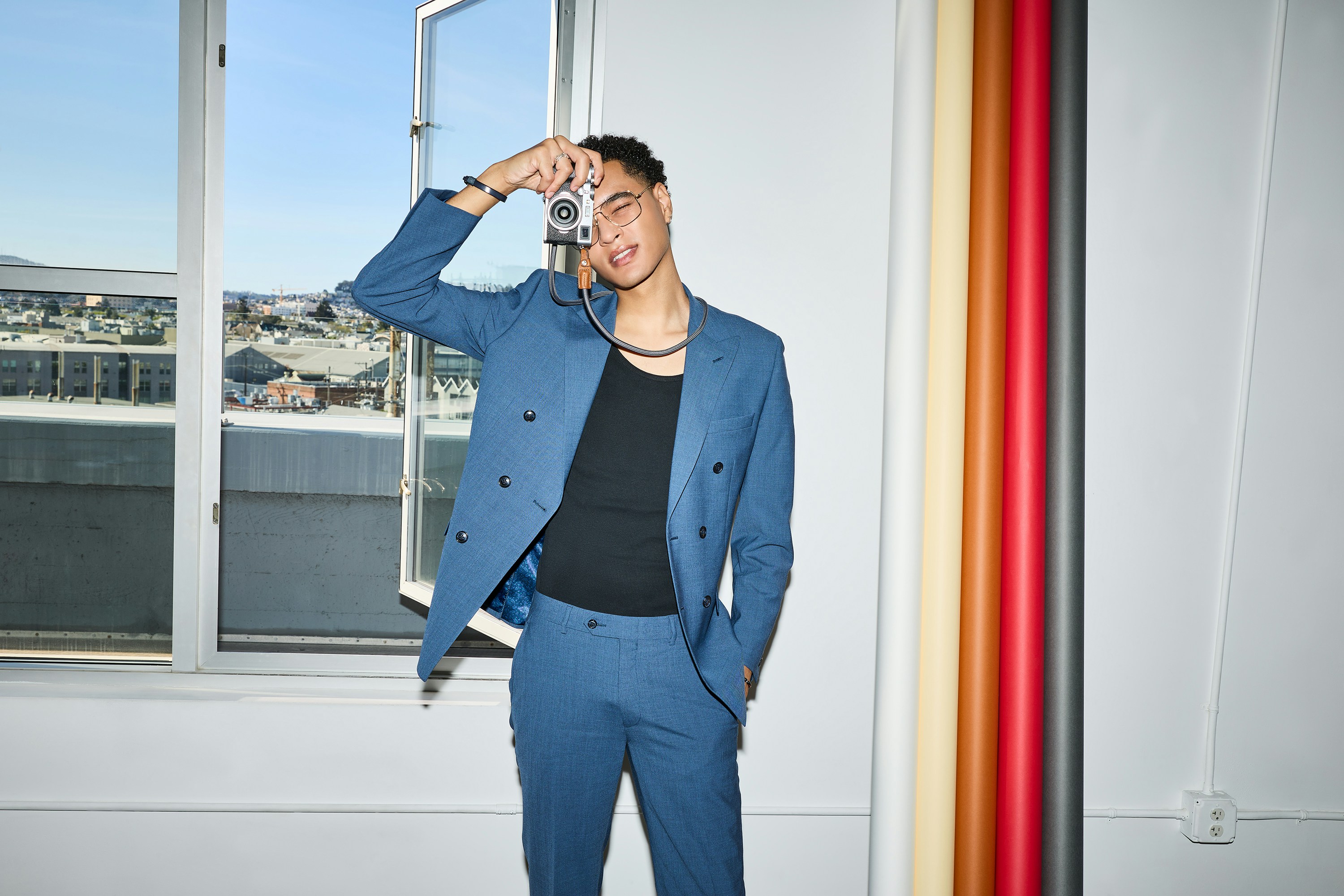 Urban Portrait with a Quiet Lens: Man in a Blue Suit Holds a Small Camera