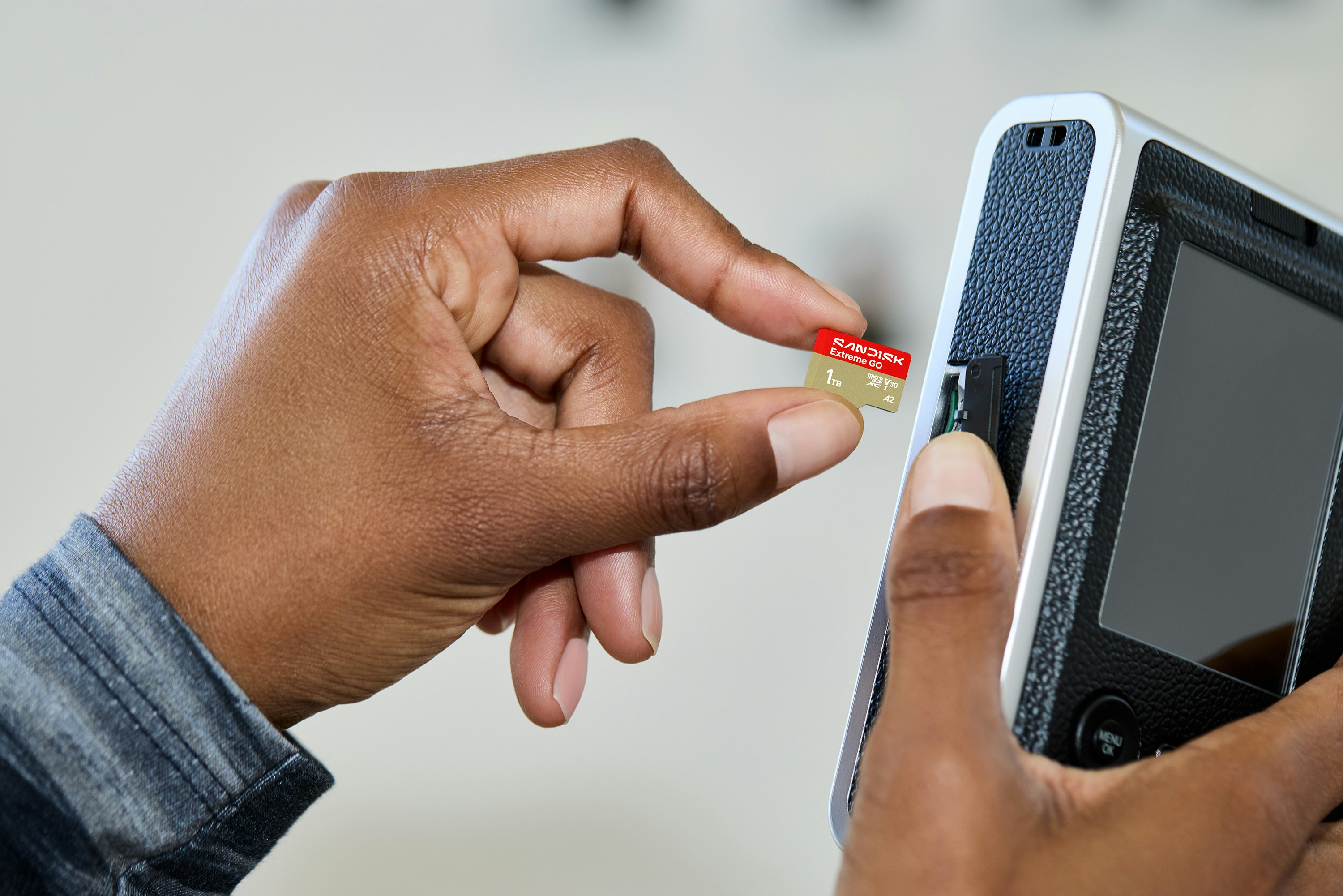 A person inserts a memory card into a digital device.