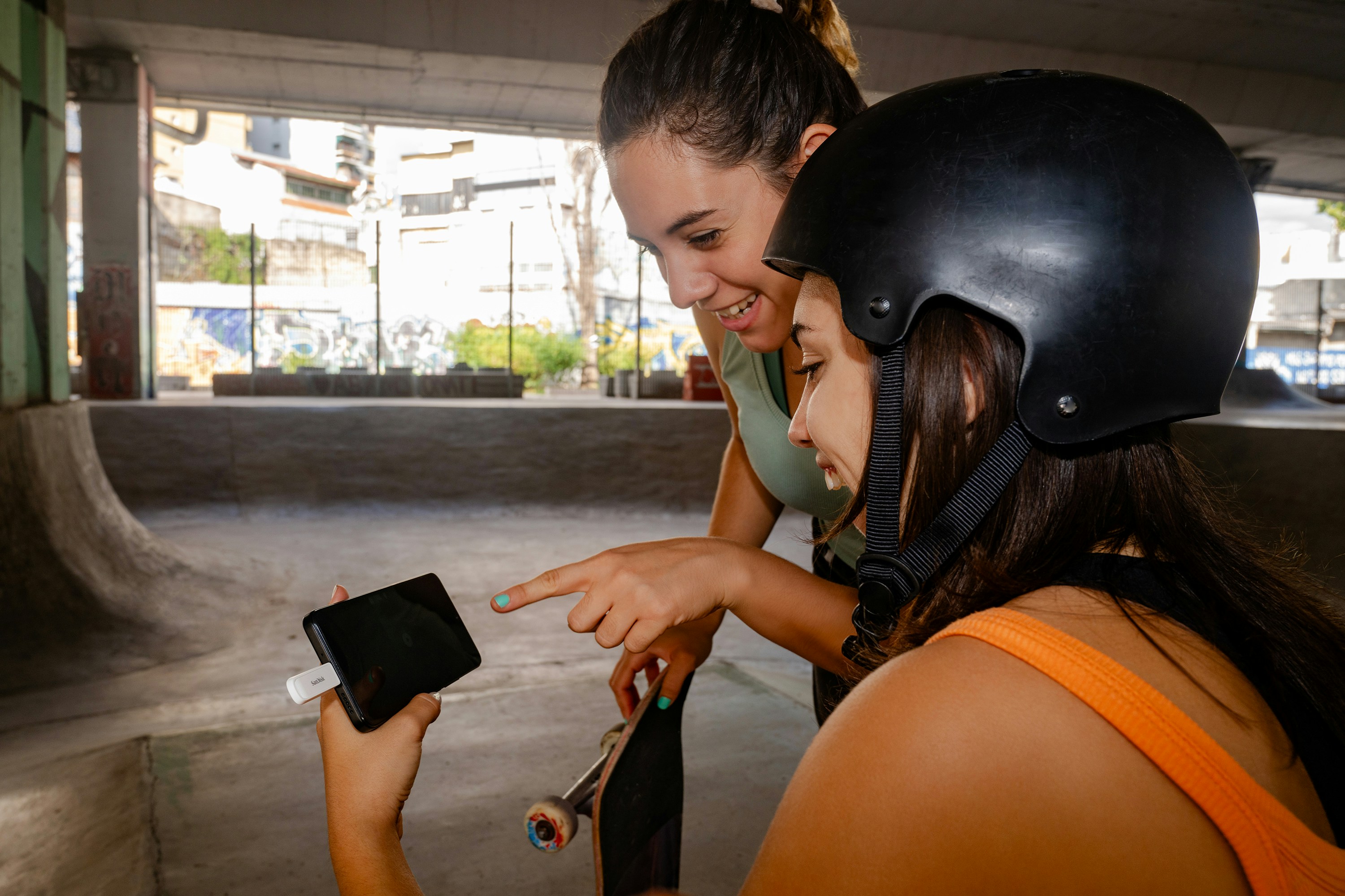 Skateboard mentors under a bridge: a mentor guides a rider’s trick close-up