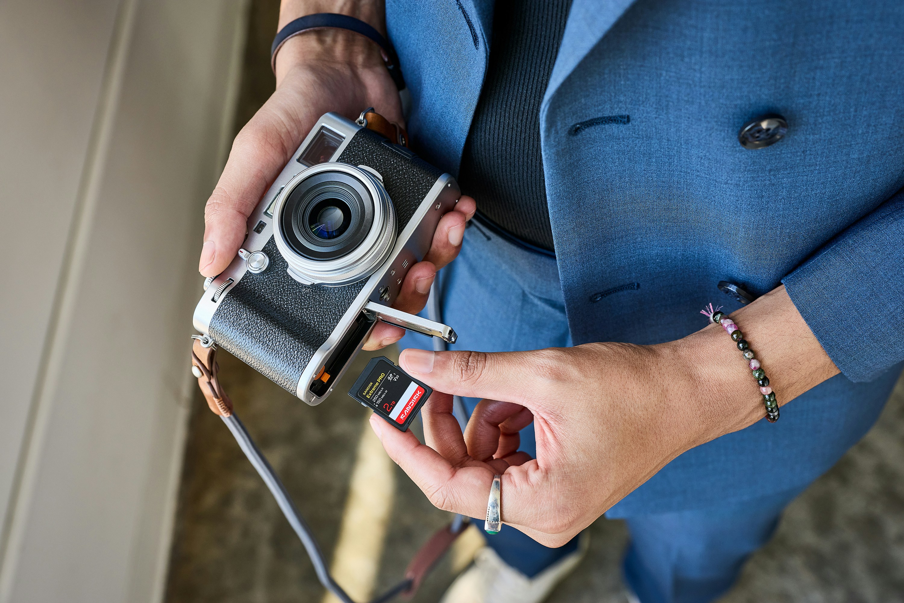 Hands inserting an sd card into a retro camera.