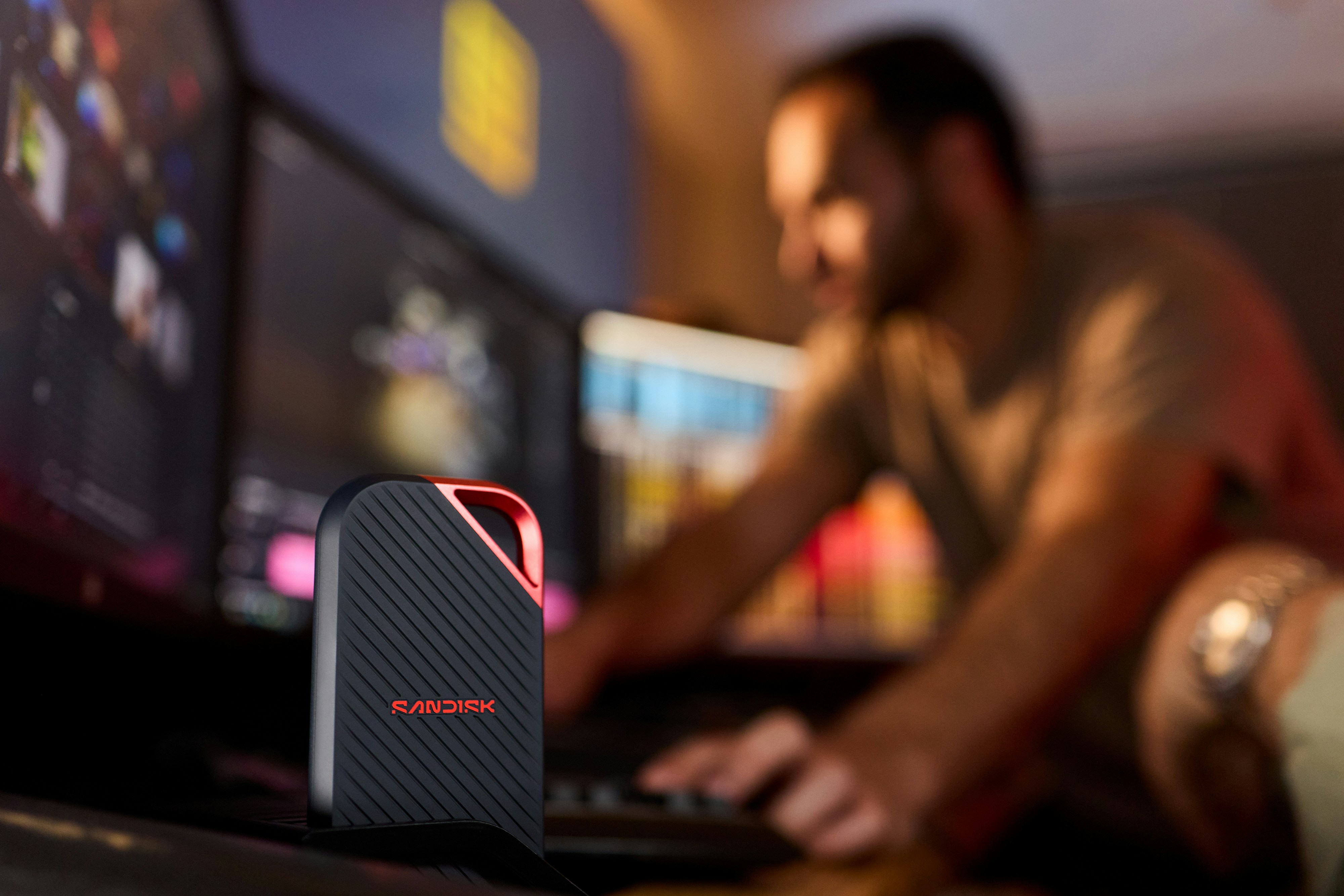 Portable ssd on desk with man working at computer.