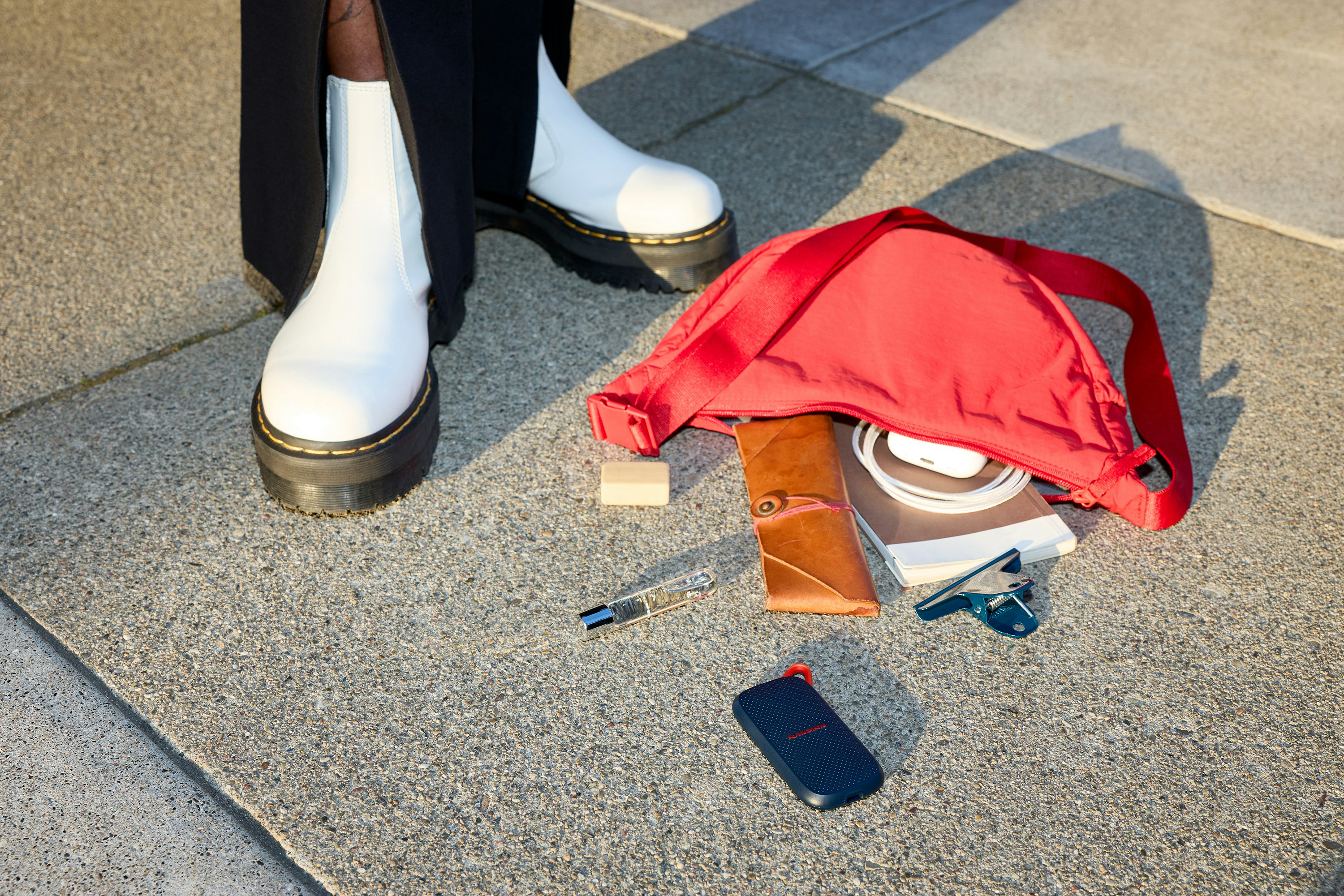 Red Backpack Reveals Everyday Gear on a Concrete Stage