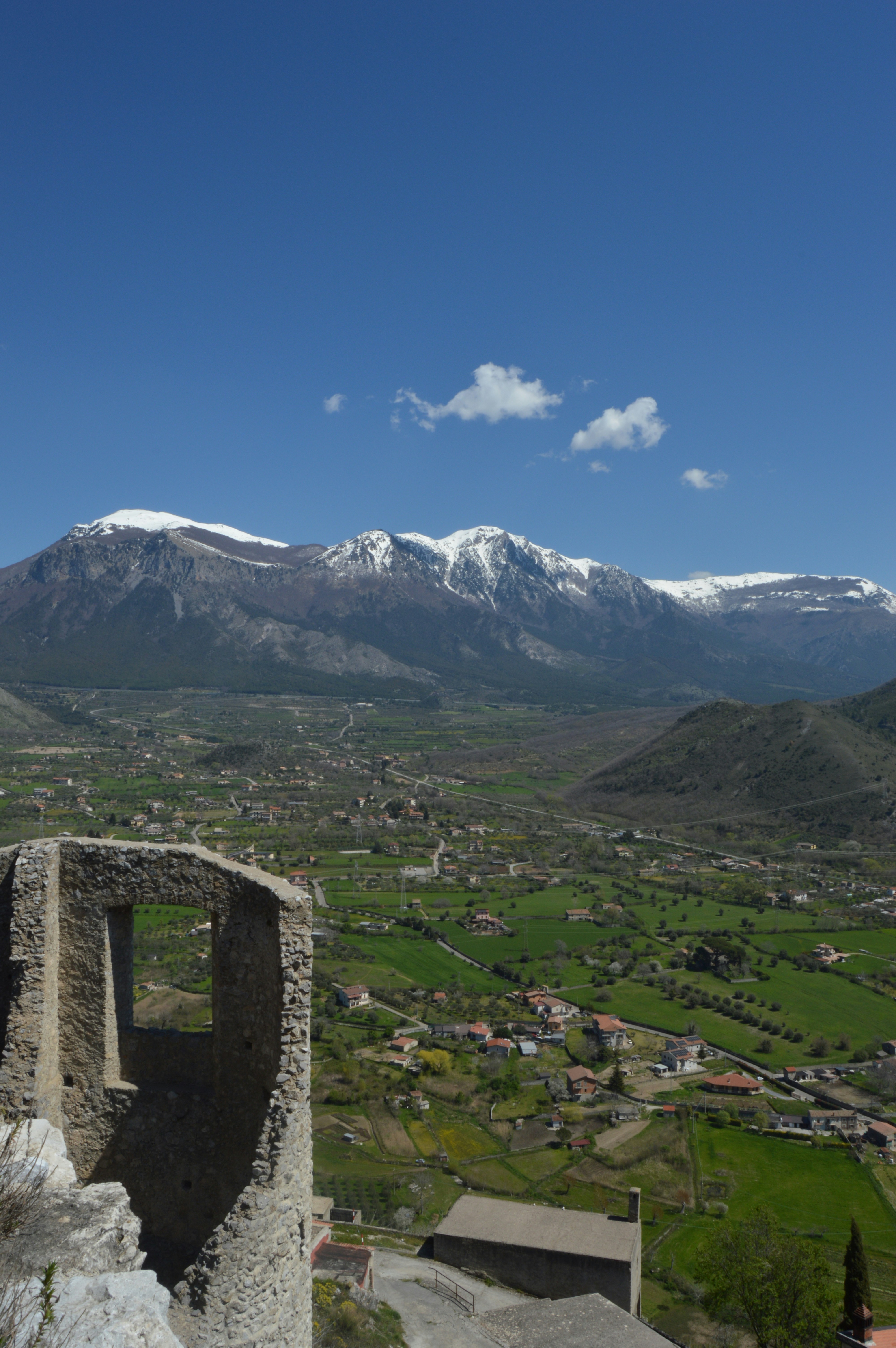 Ruins Overlooking a Verdant Valley Beneath Snow-Capped Peaks
