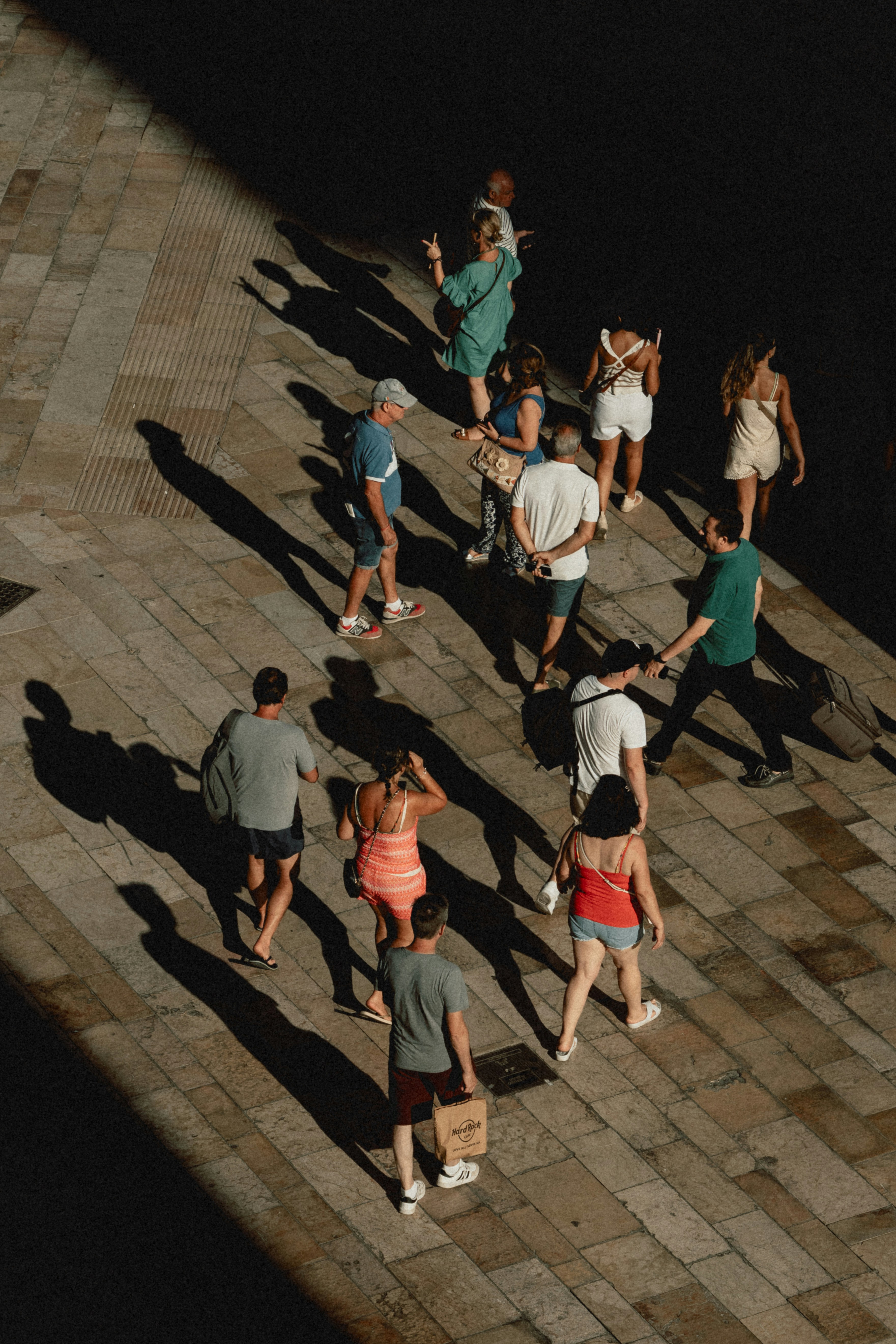 Shadows and Stride: Evening Pedestrians Cast Long Courtyard Lines