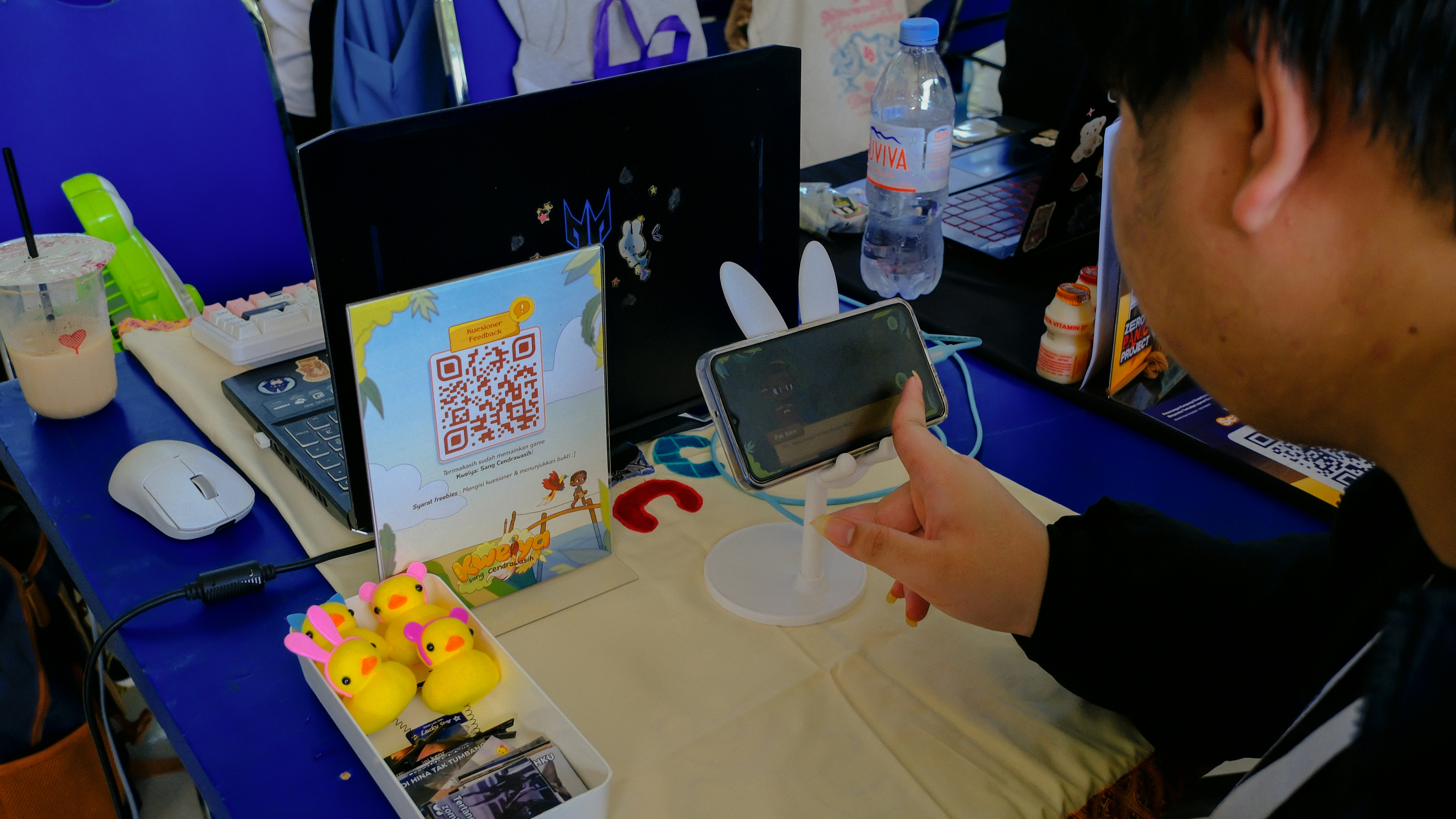 Handheld Pay: A Cashier's Display Amid Toy Ducks and QR Tech