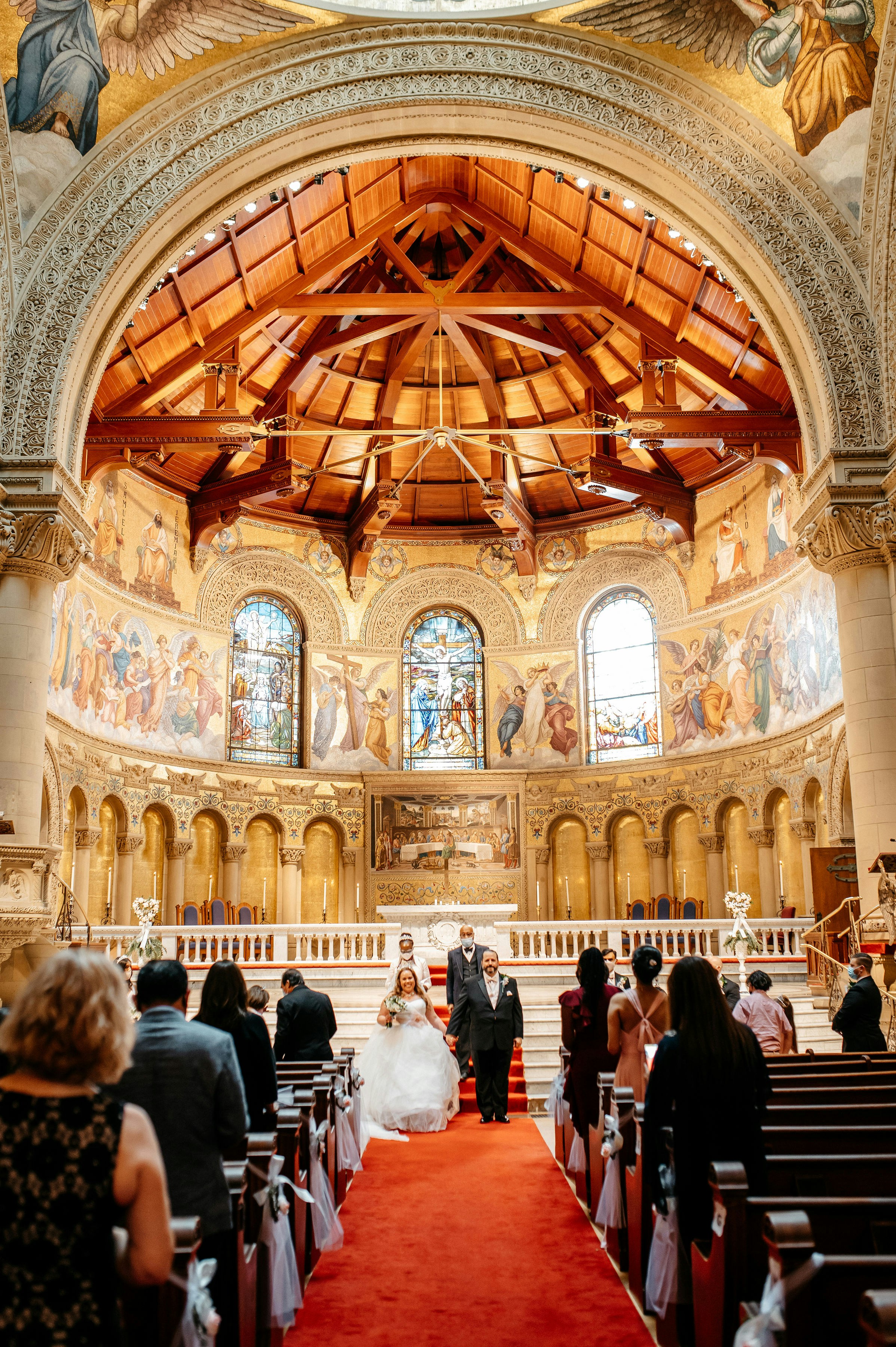 Bride walks down grand church aisle with father.