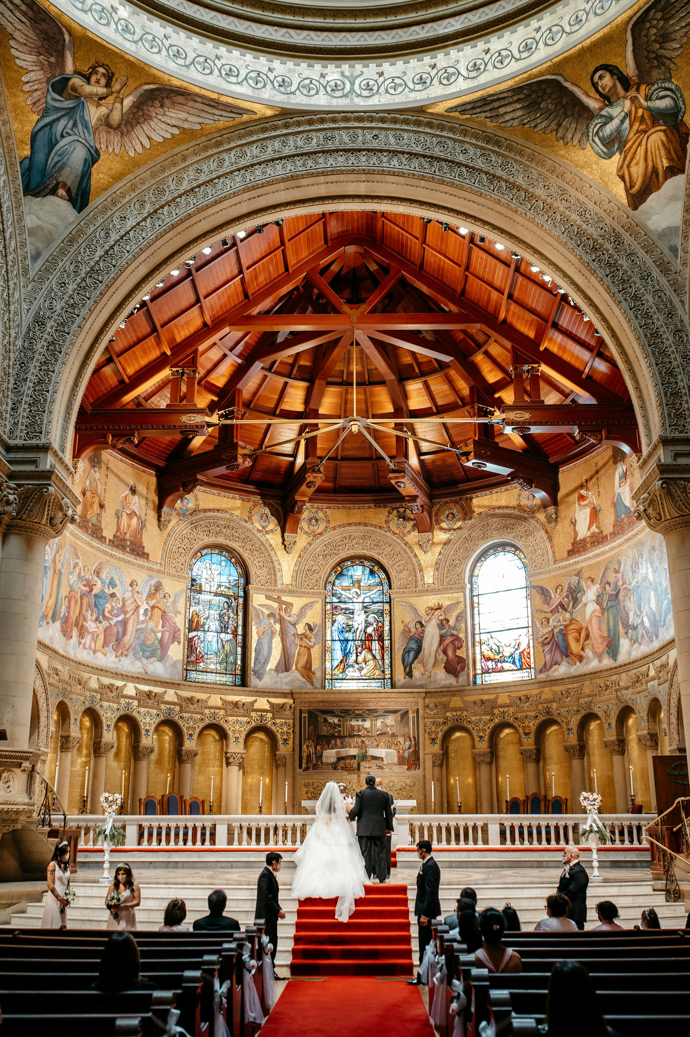 Ceremonial Convergence: Bride and Groom Ascend the Red Carpet in a Basilica of Painted Stories
