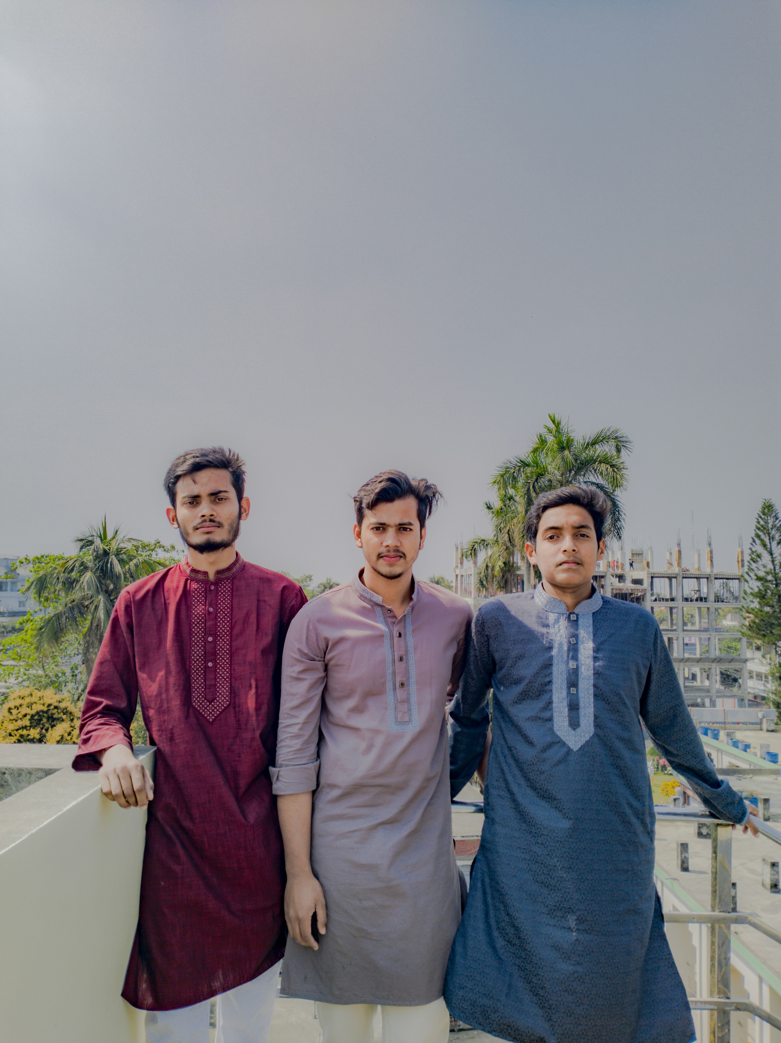 Three friends in traditional kameez on a sunlit rooftop