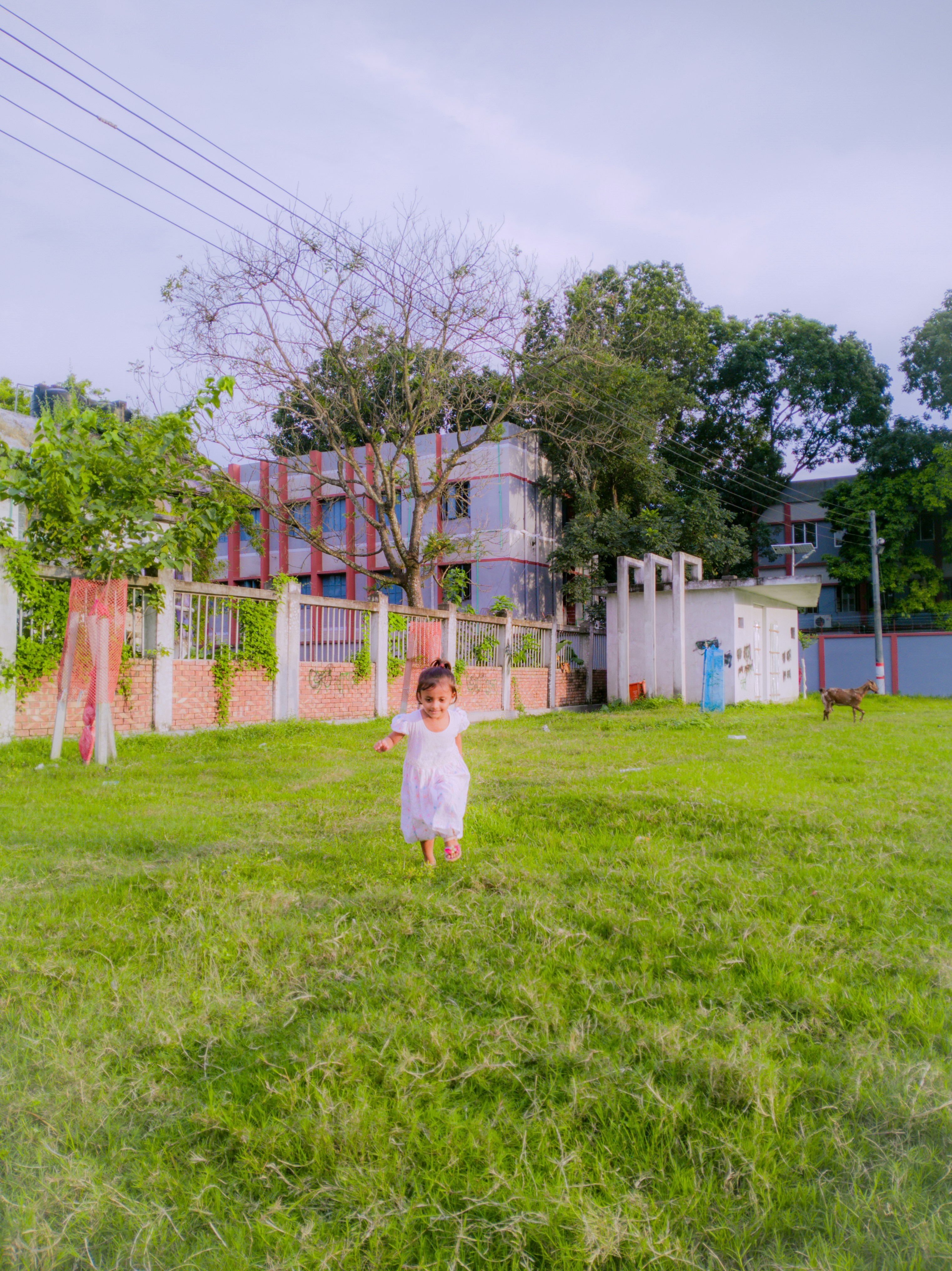 A young child runs across a green grassy field.