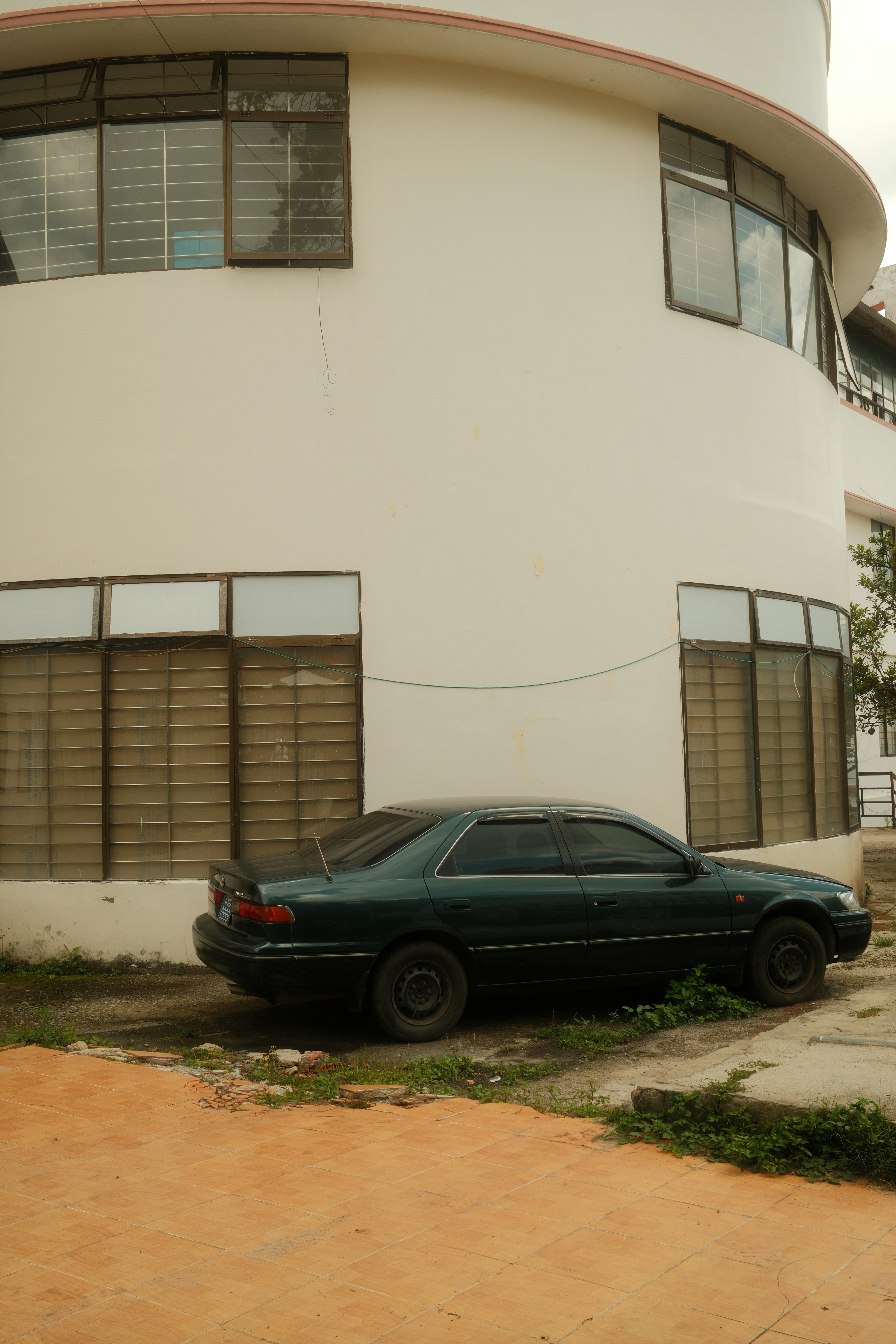 Curved facade, parked sedan: a quiet urban vignette