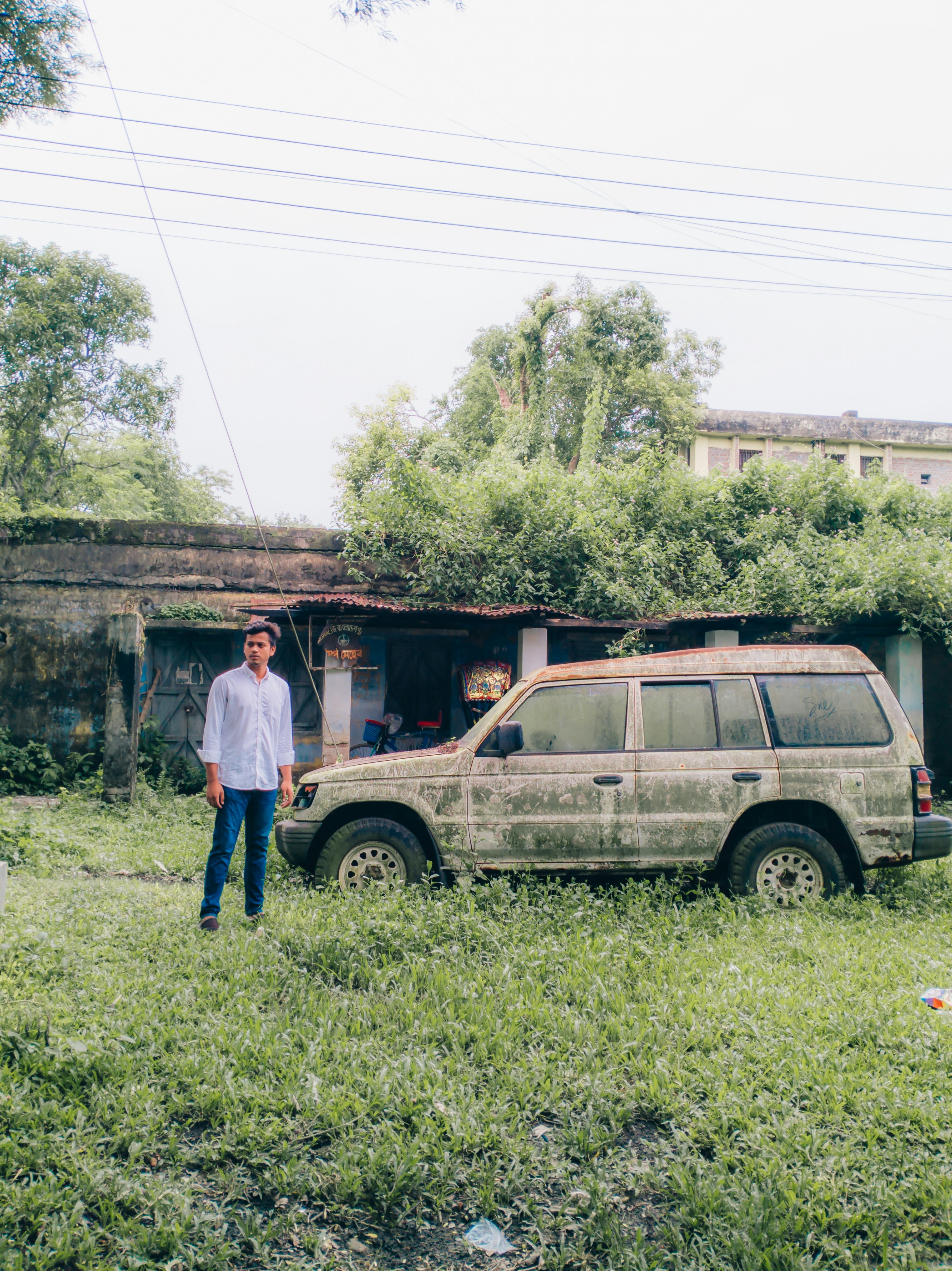Man beside a muddy SUV in a rural compound at dusk
